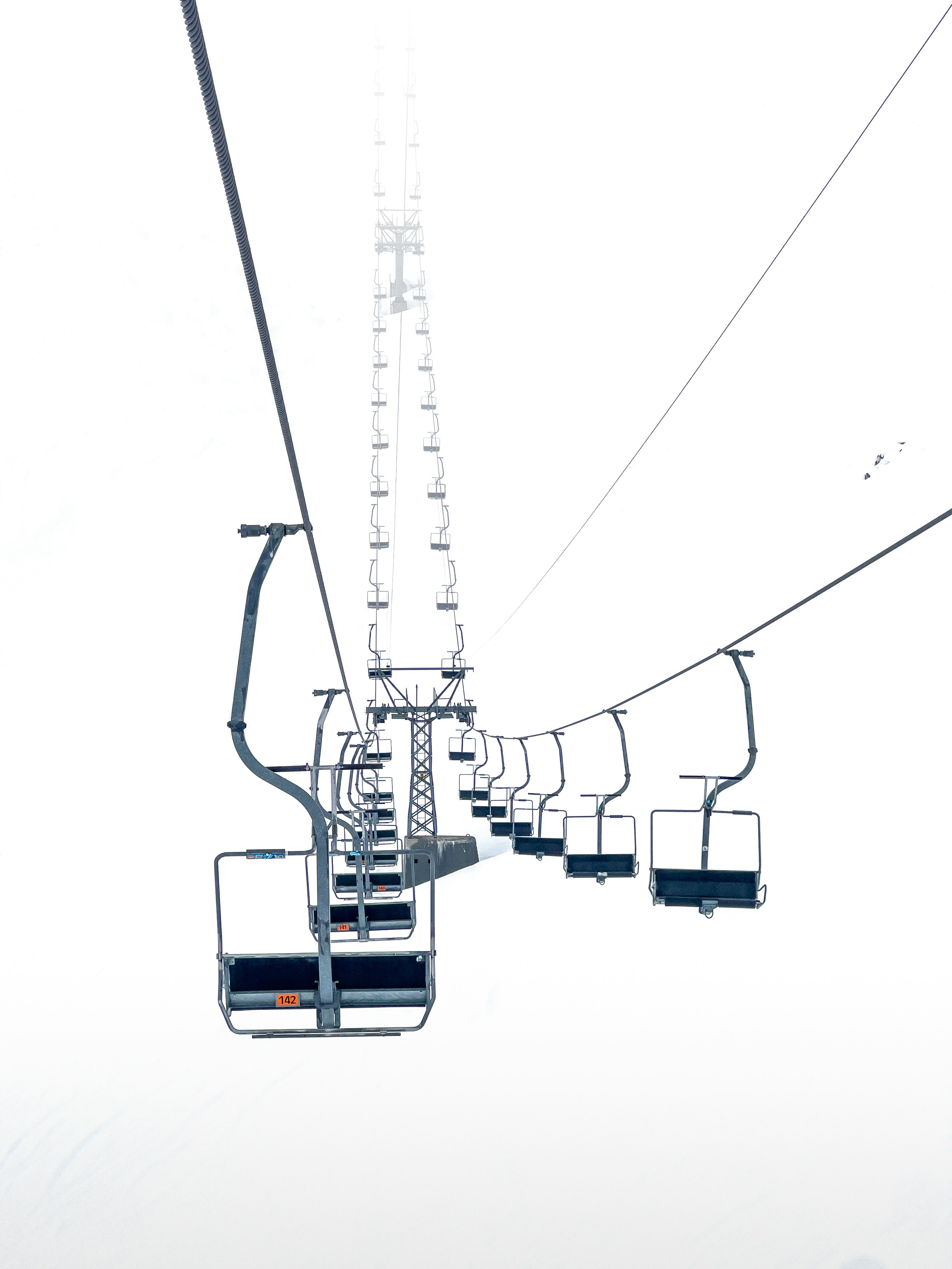 Empty ski chairlift ascending through a foggy landscape, creating a sense of solitude and anticipation.