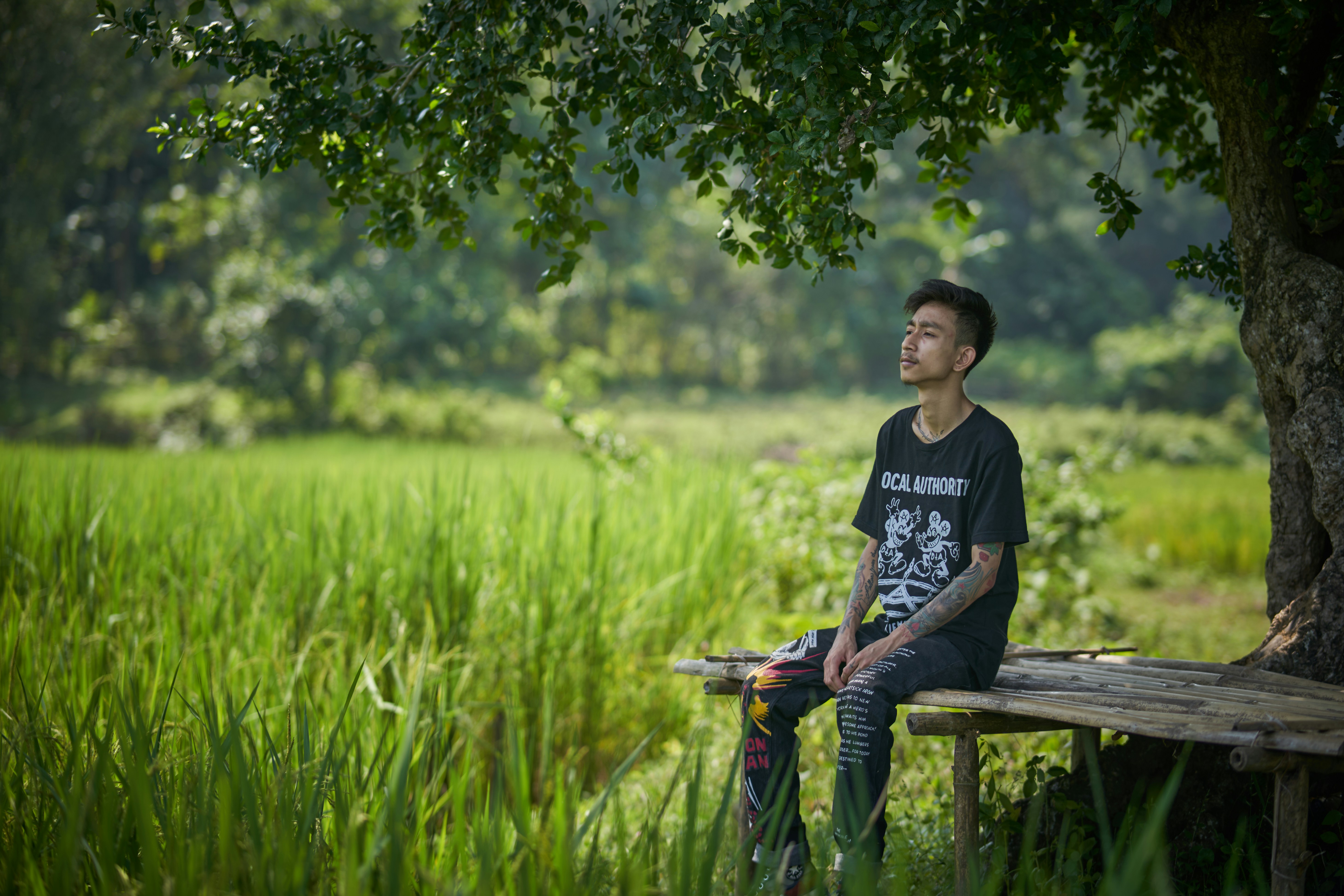 Enjoying in peace with nature 😇 | a man sitting on a wooden bench under a tree