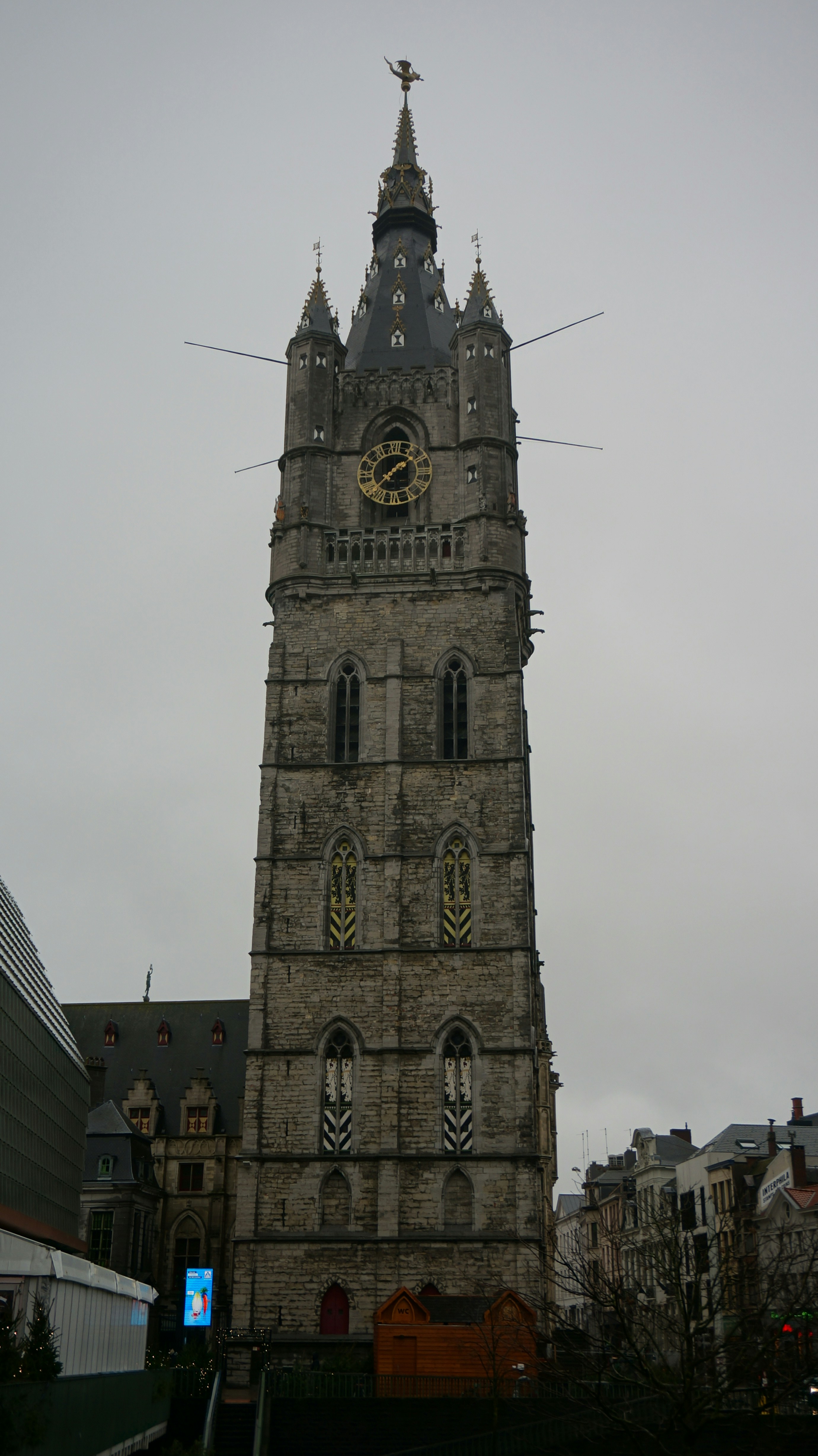 Clockwork Gothic: The Tower's Golden Dial Against Gray Skies