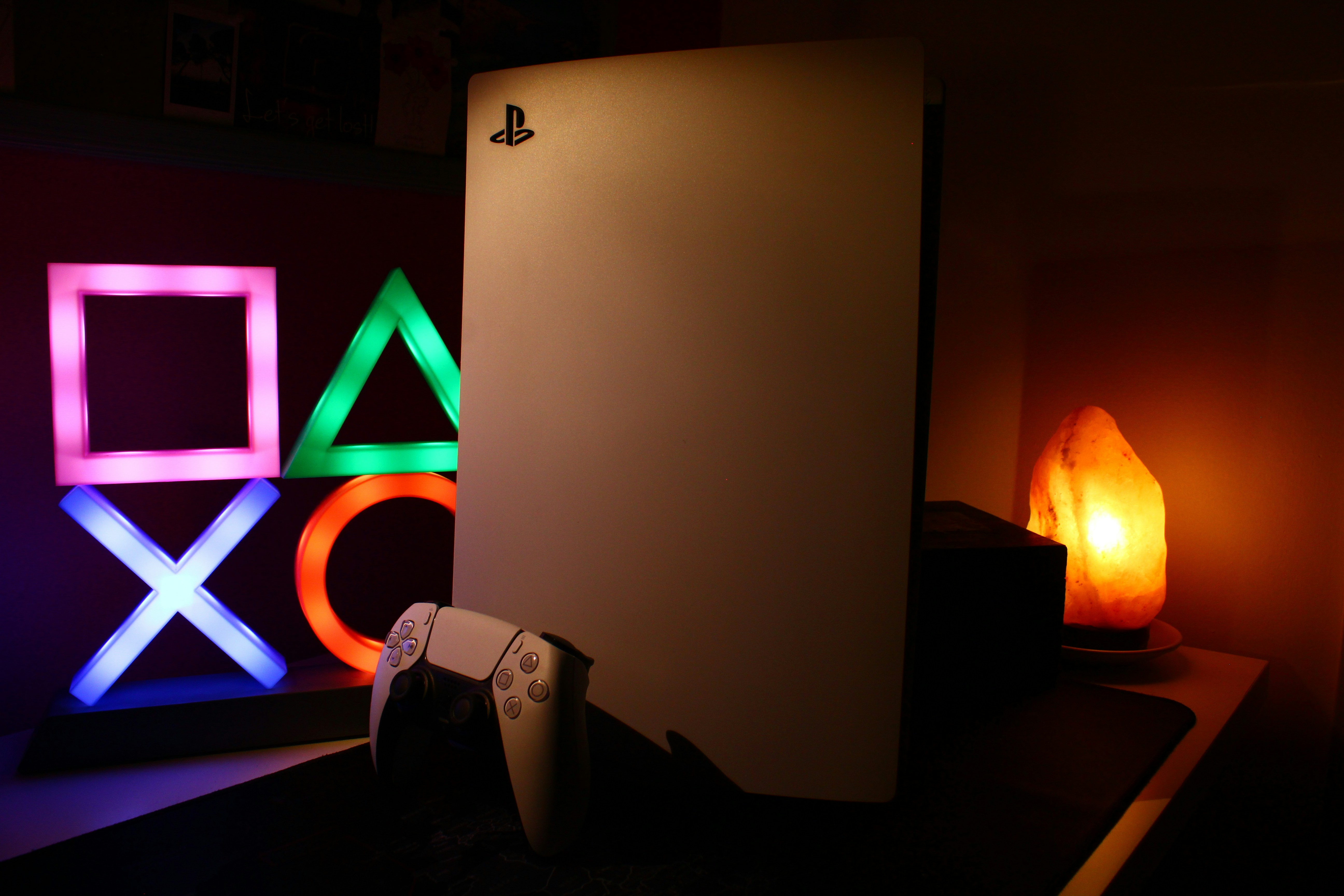 PlayStation 5 in warm light and a lamp representing playstation button icons on the side