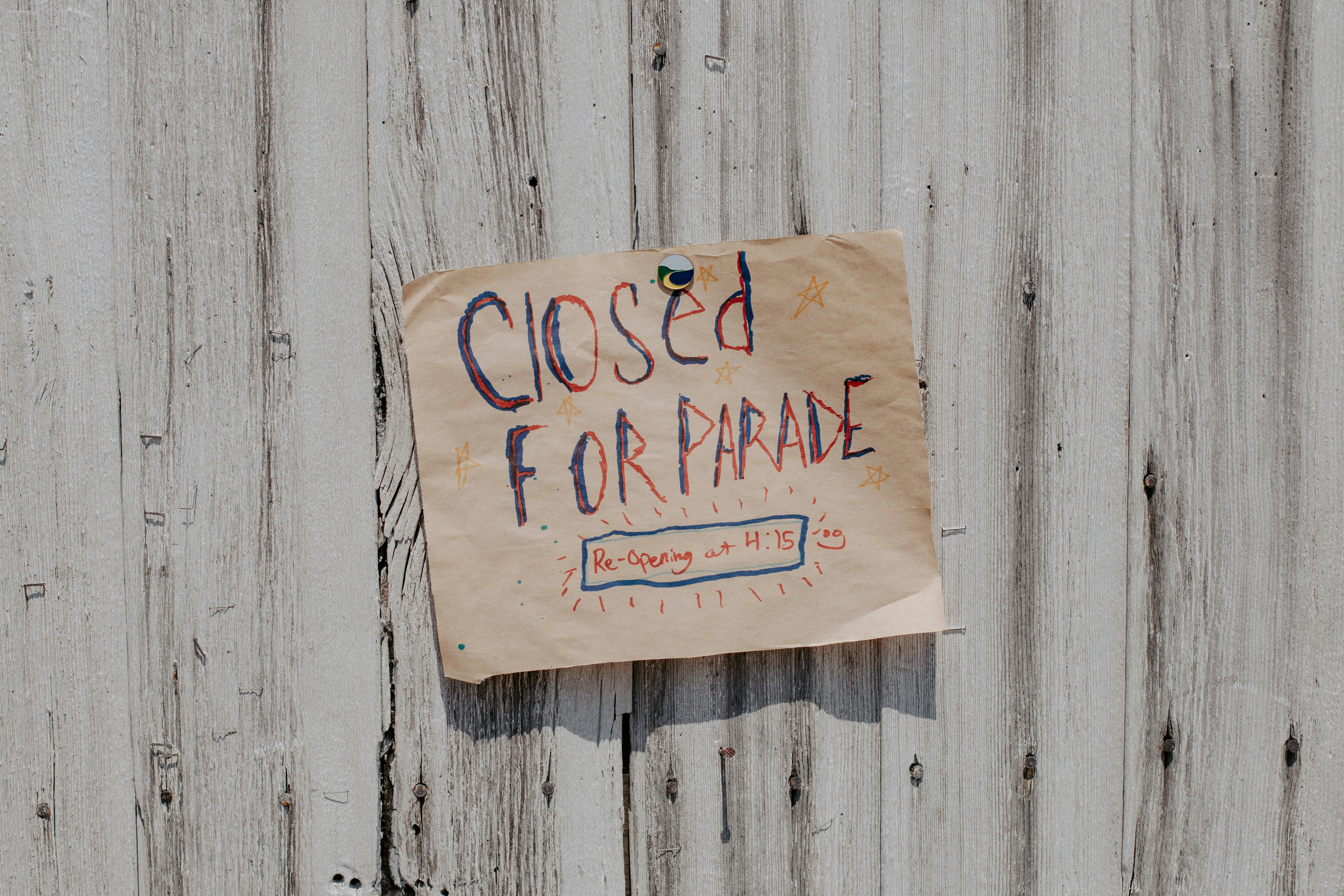 A sign posted on a wooden fence that says closed for parade photo ...