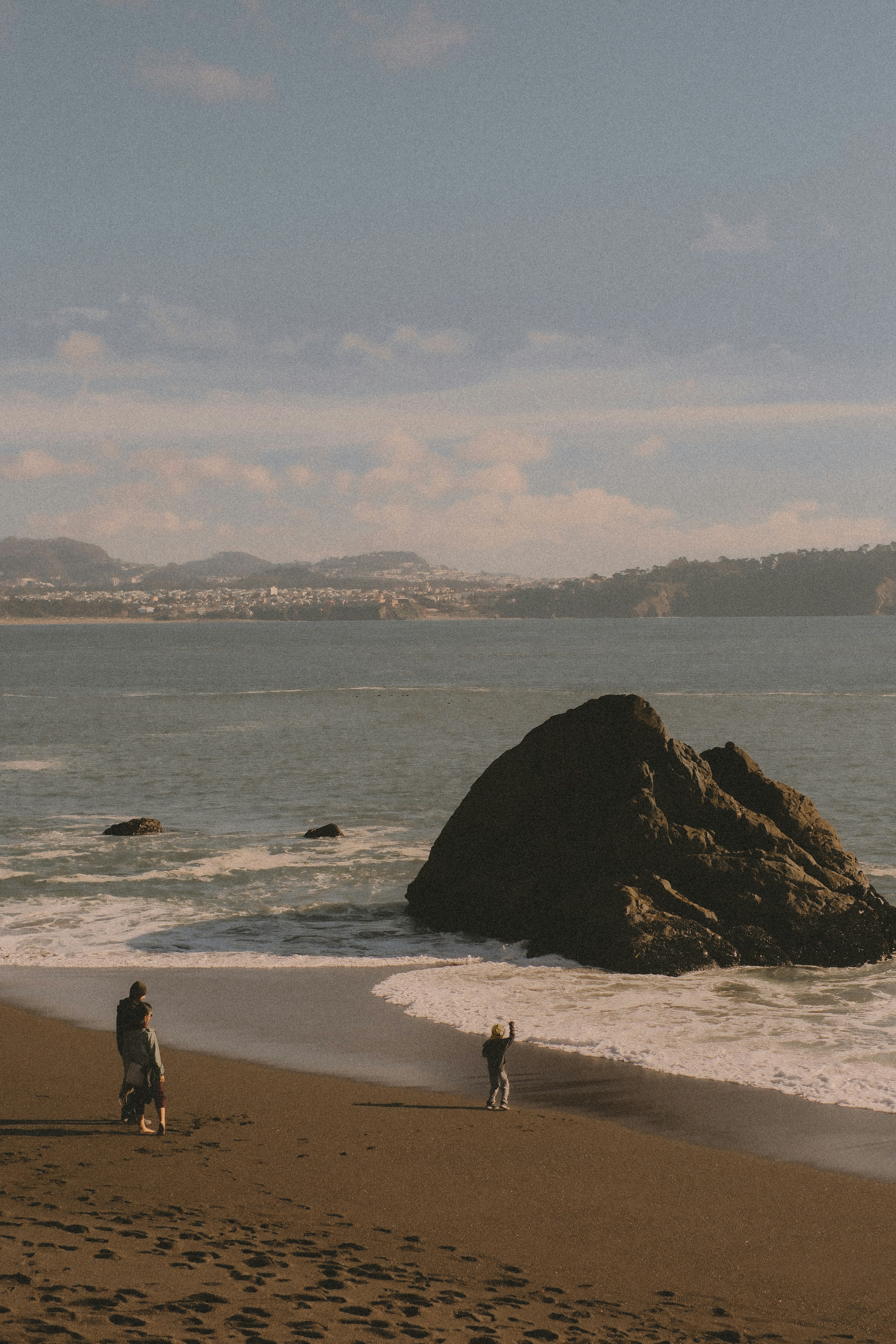 Granite Sentinel by the Shore: A Coastal Moment with People and Sea