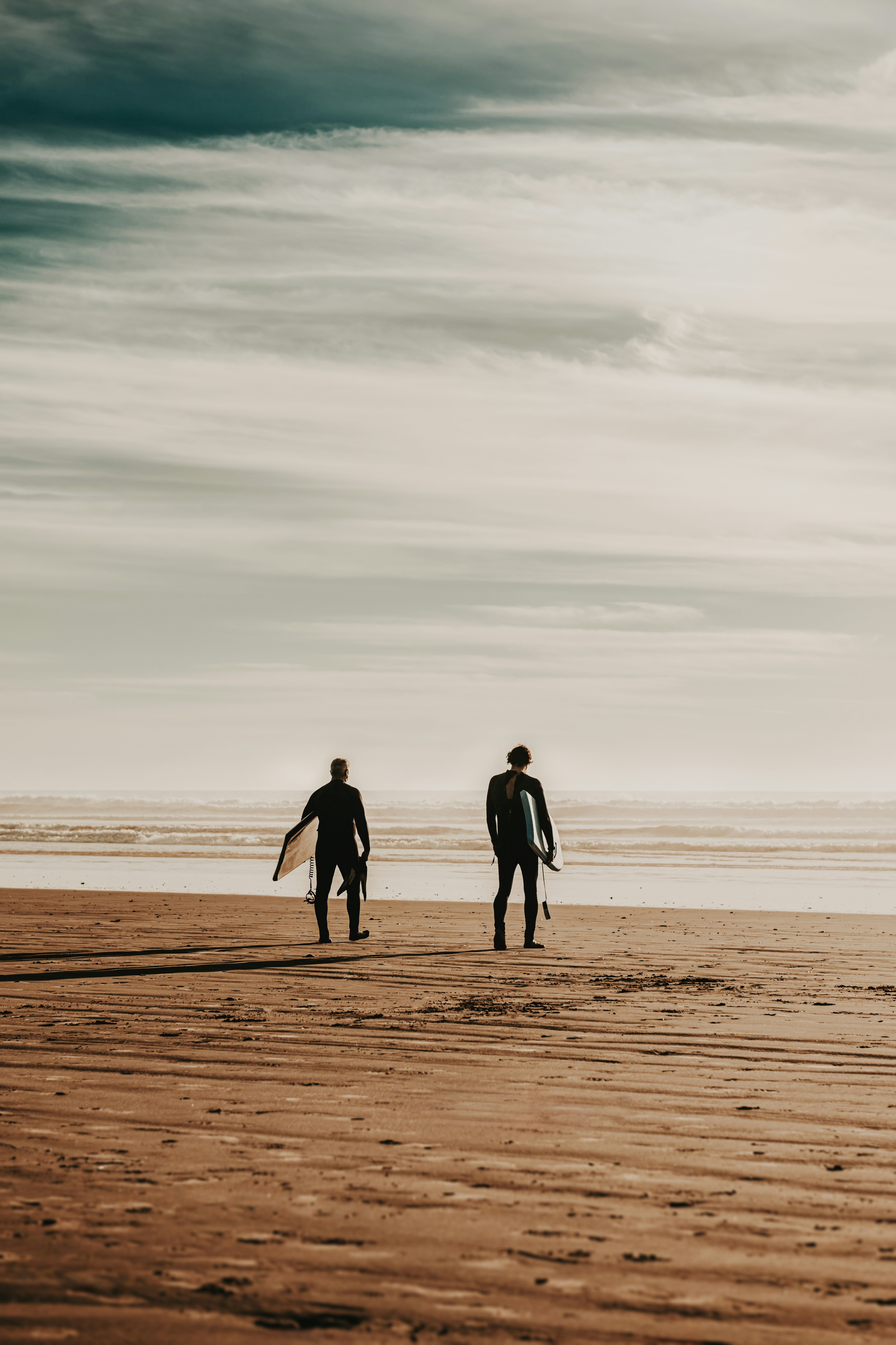 Two surfers walking on the beach with their boards photo – Free Ocean ...