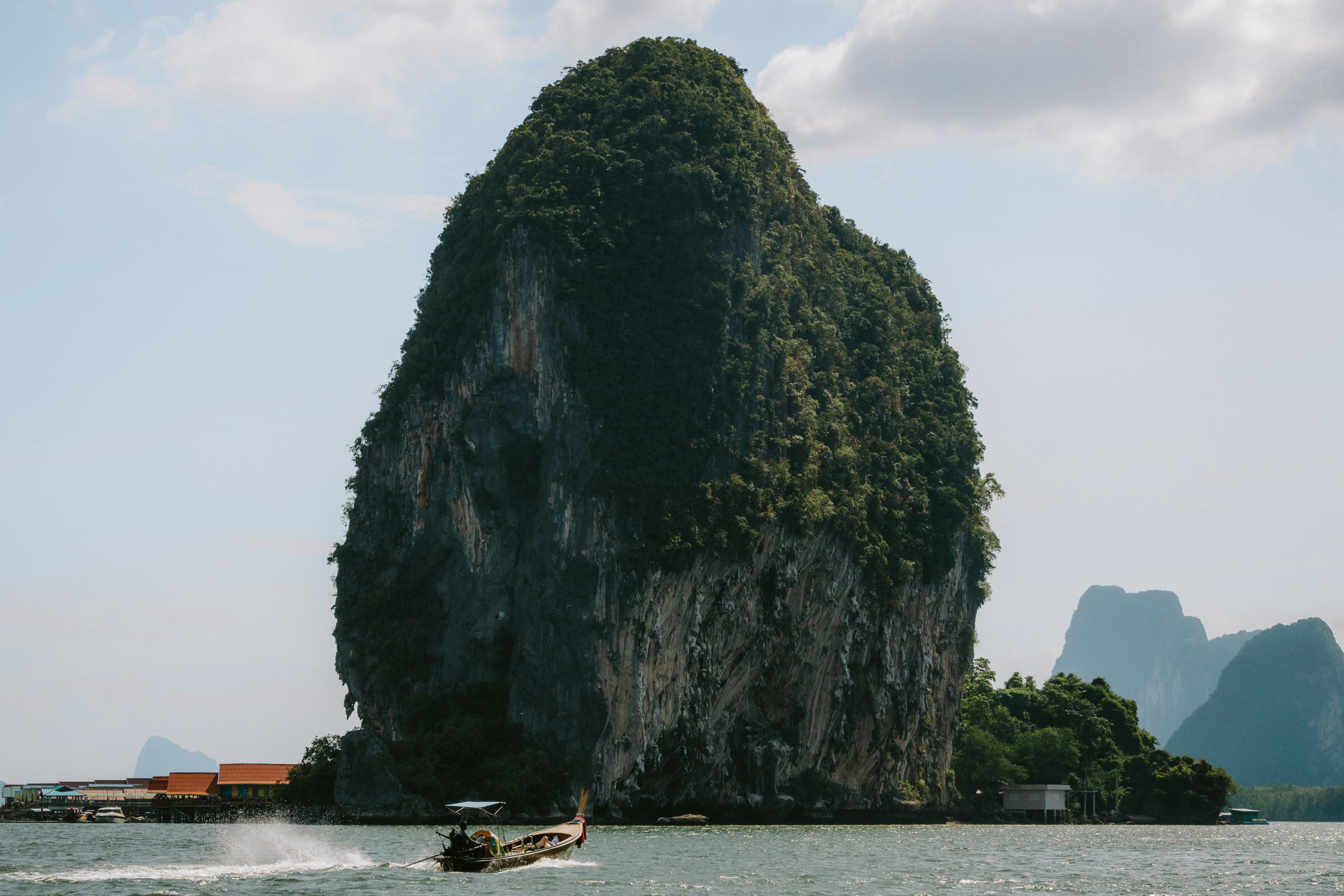A boat traveling past a large rock formation in the ocean photo – Free ...
