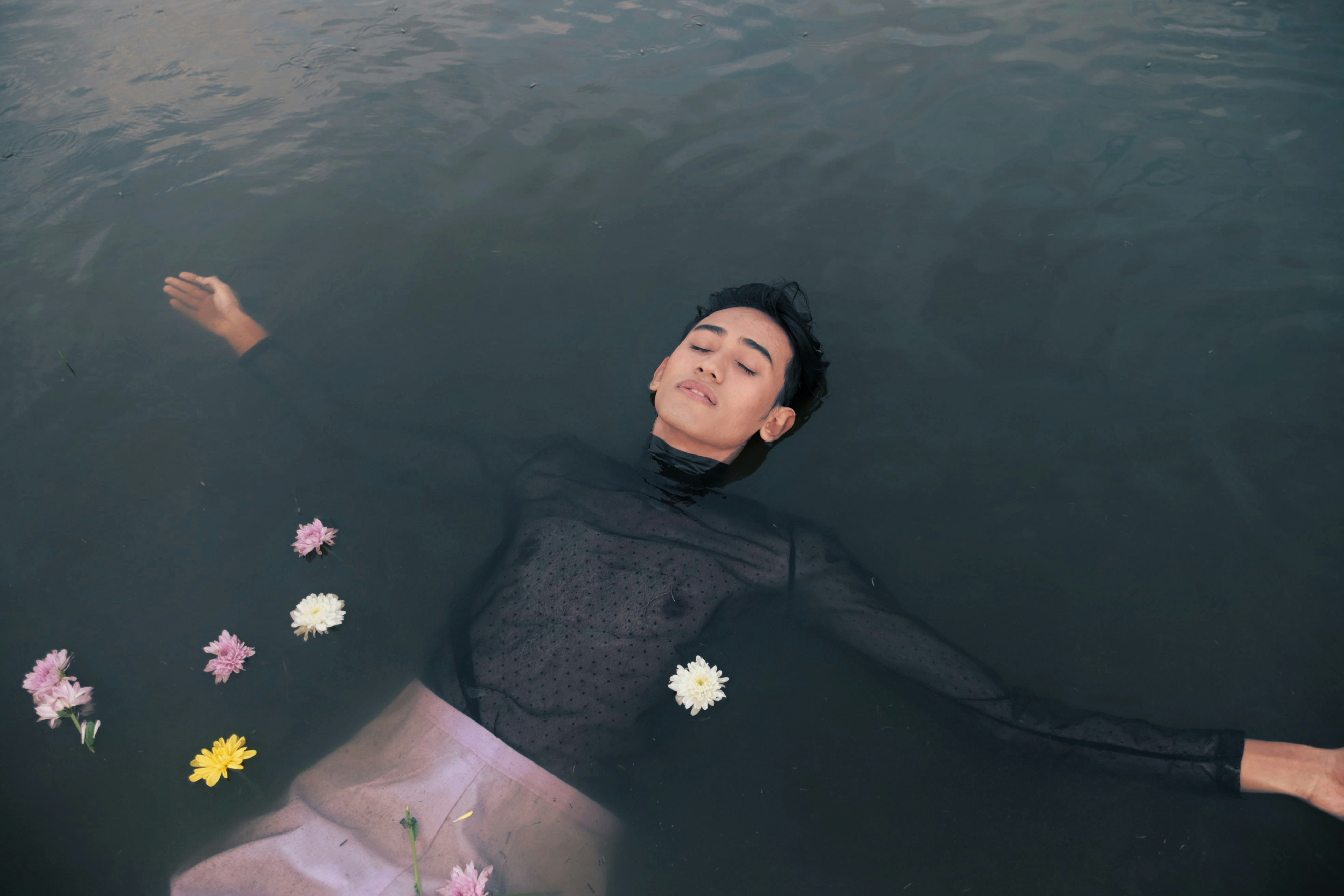 A man floating on top of a body of water photo – Free Woman Image on ...