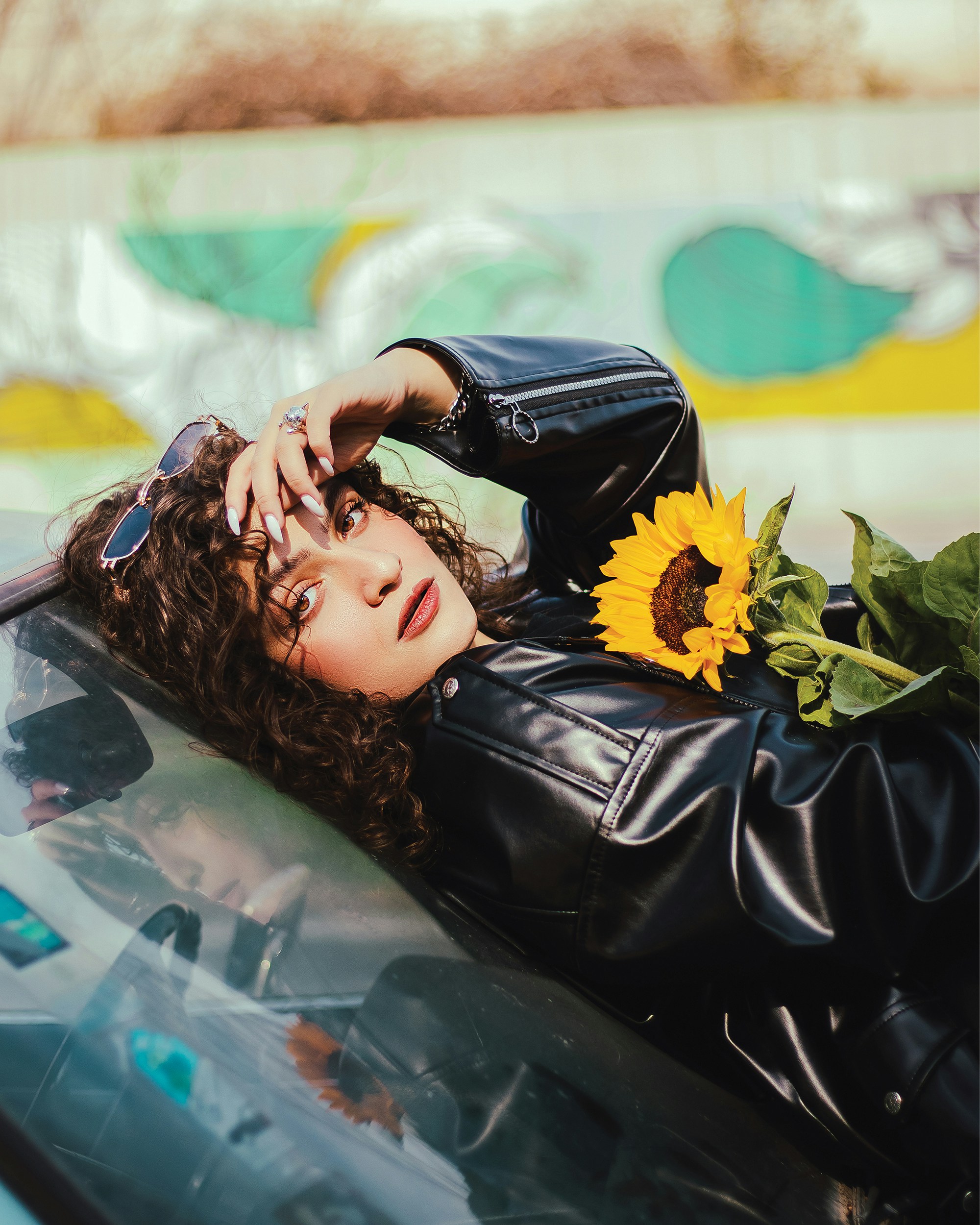 Sunflower Gaze on a Leather Hood: A Graffiti-Backed Portrait