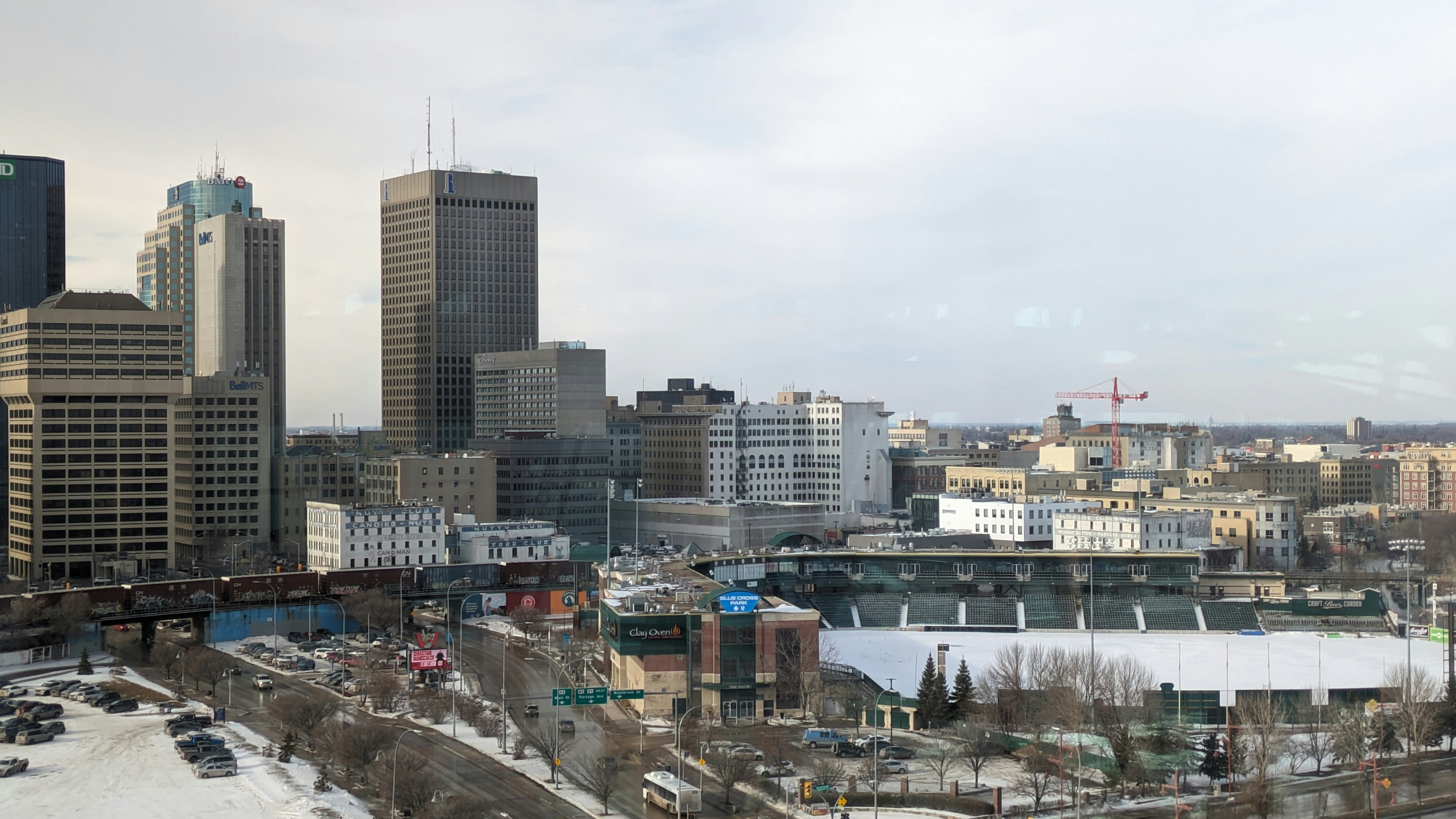 Snow-dusted cityscape with towering buildings under a cloudy sky.