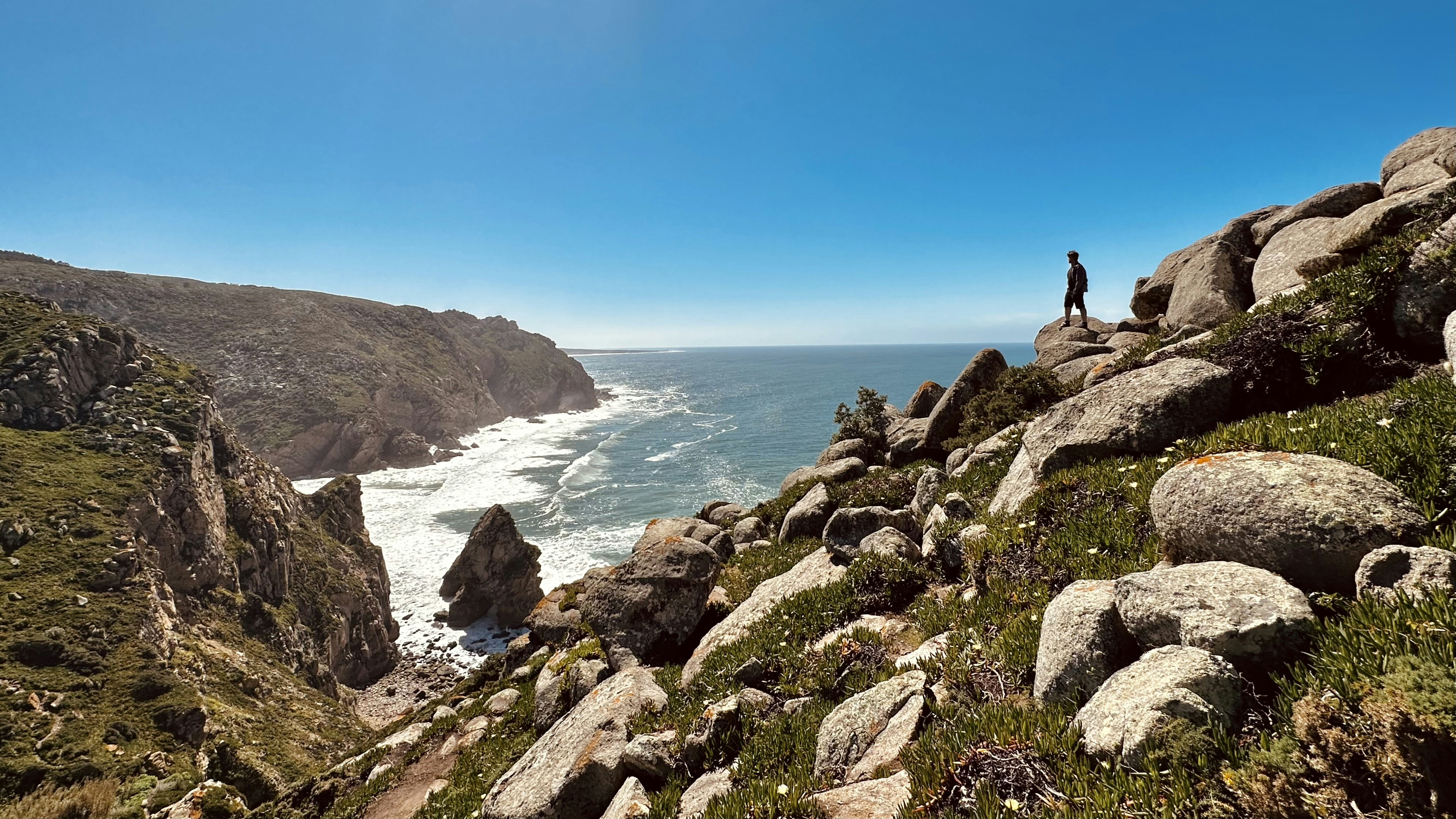 Cliffside Overlook: Lone figure on weathered rocks above the Pacific