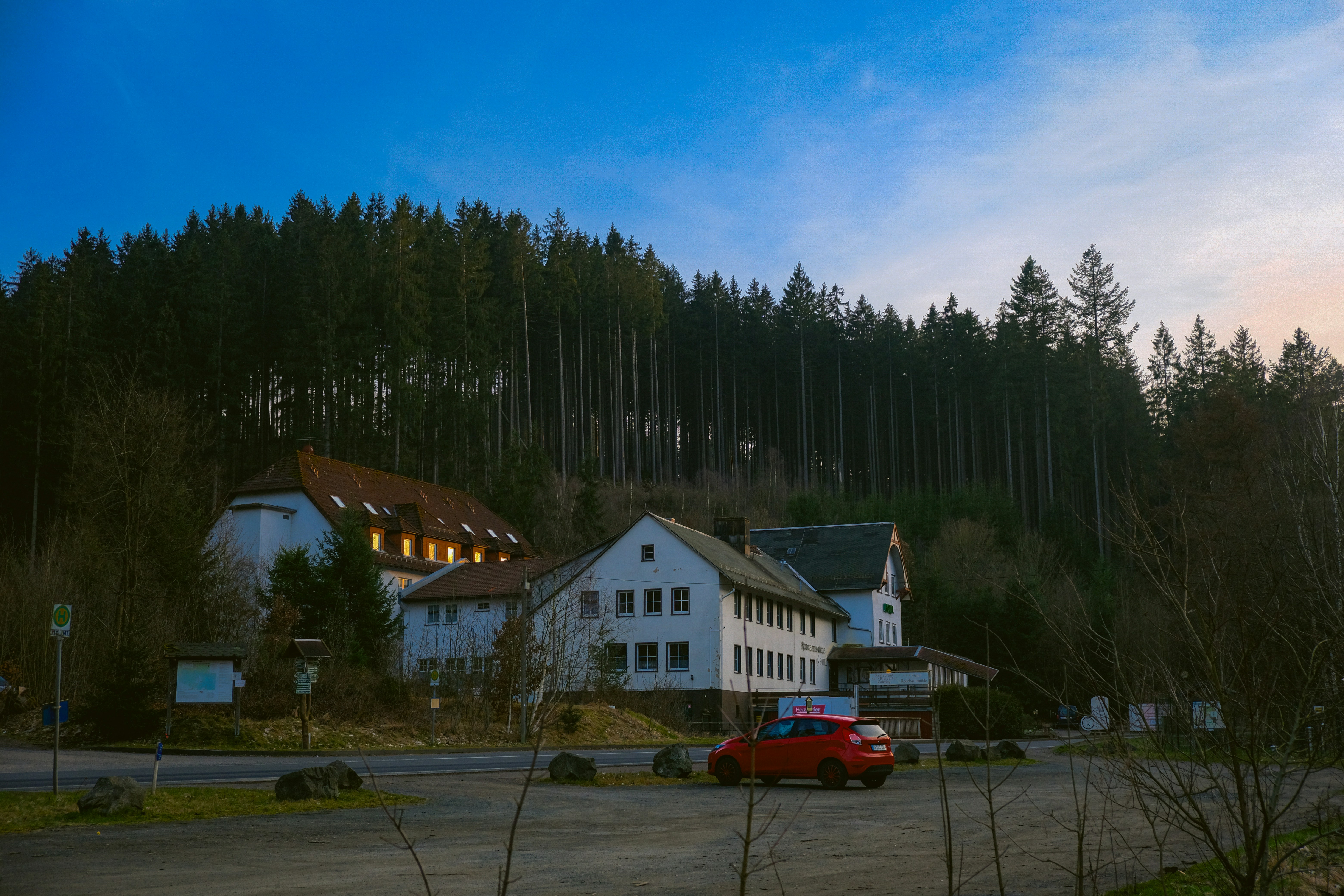 Twilight Quiet: Red Car at the Edge of a Pine-Forest Village