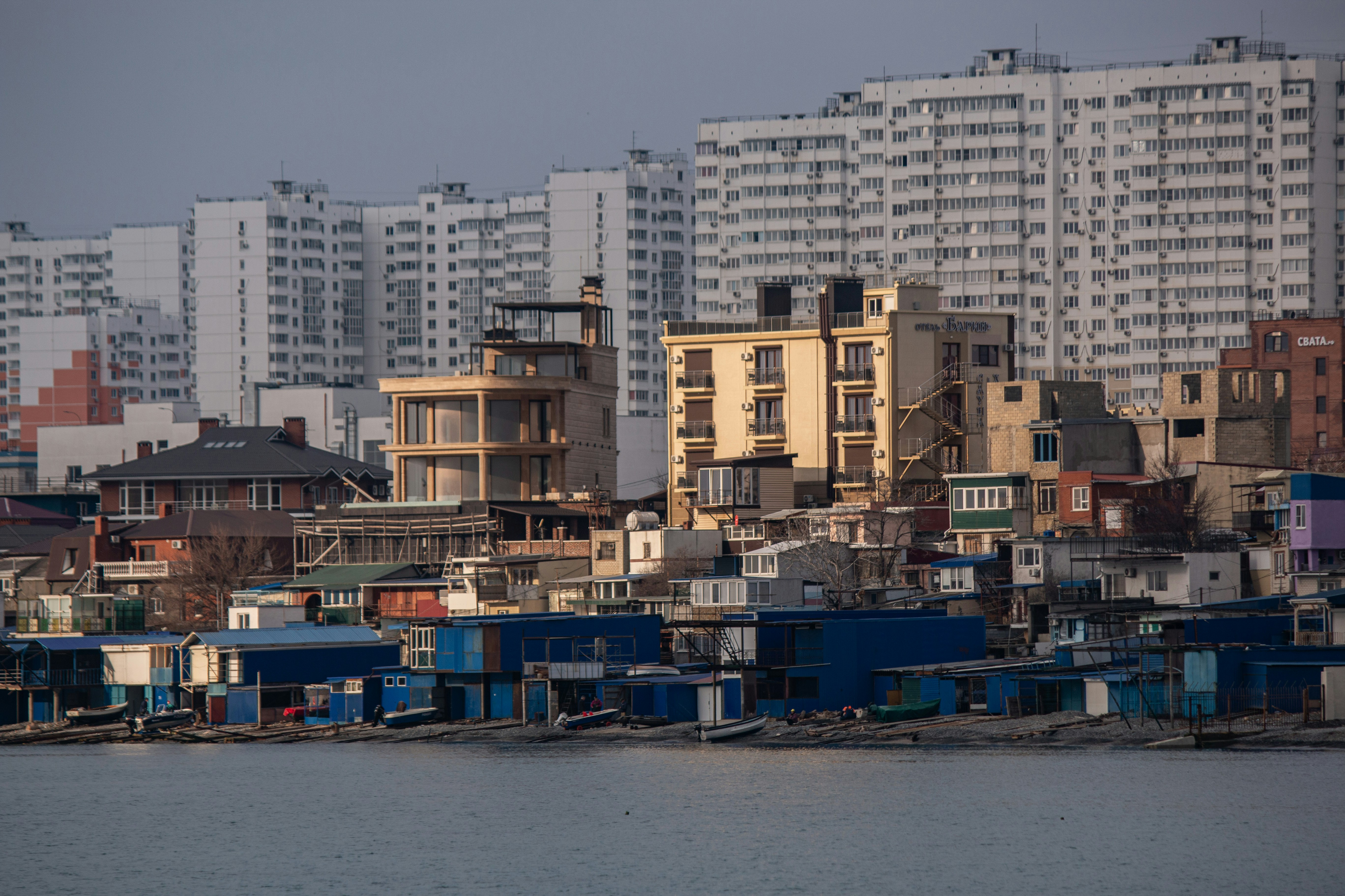Waterfront Patchwork: Sunlit Shacks Meet a Densely Packed Riverside Quarter