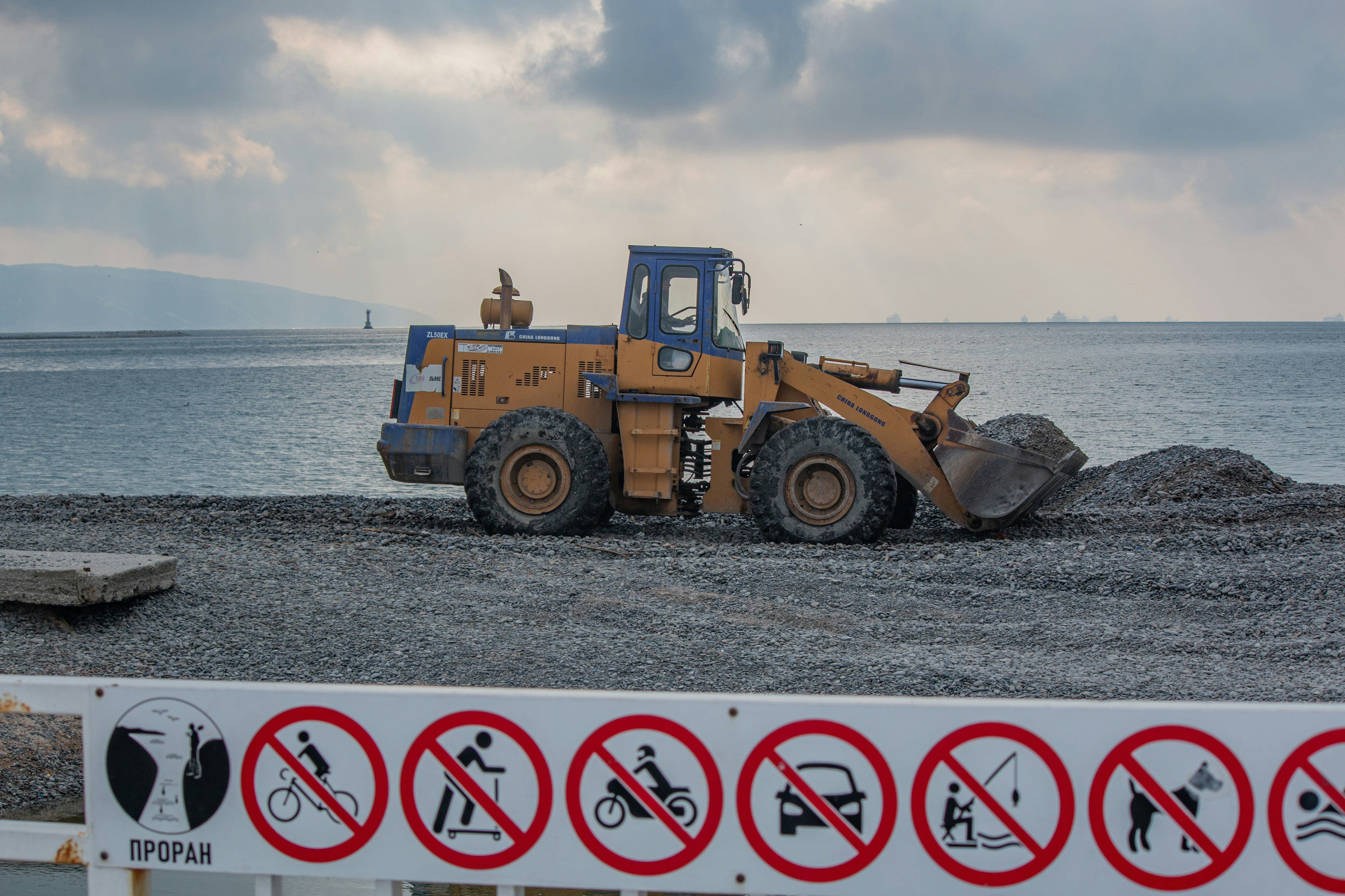 A bulldozer sitting on top of a beach next to the ocean photo – Free ...