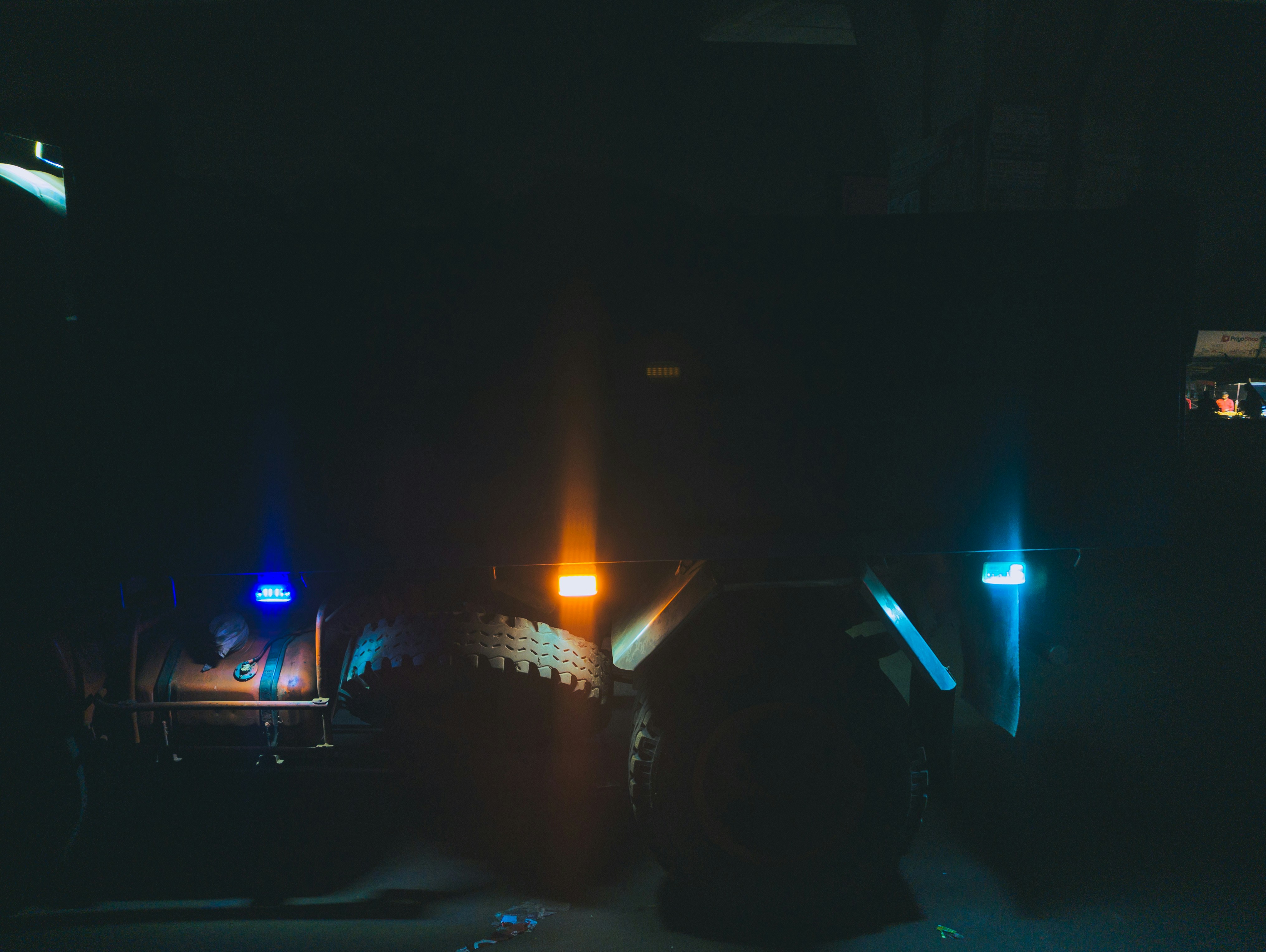 A dimly lit scene featuring a heavy-duty truck, with vibrant blue and orange lights illuminating its silhouette against the darkness.