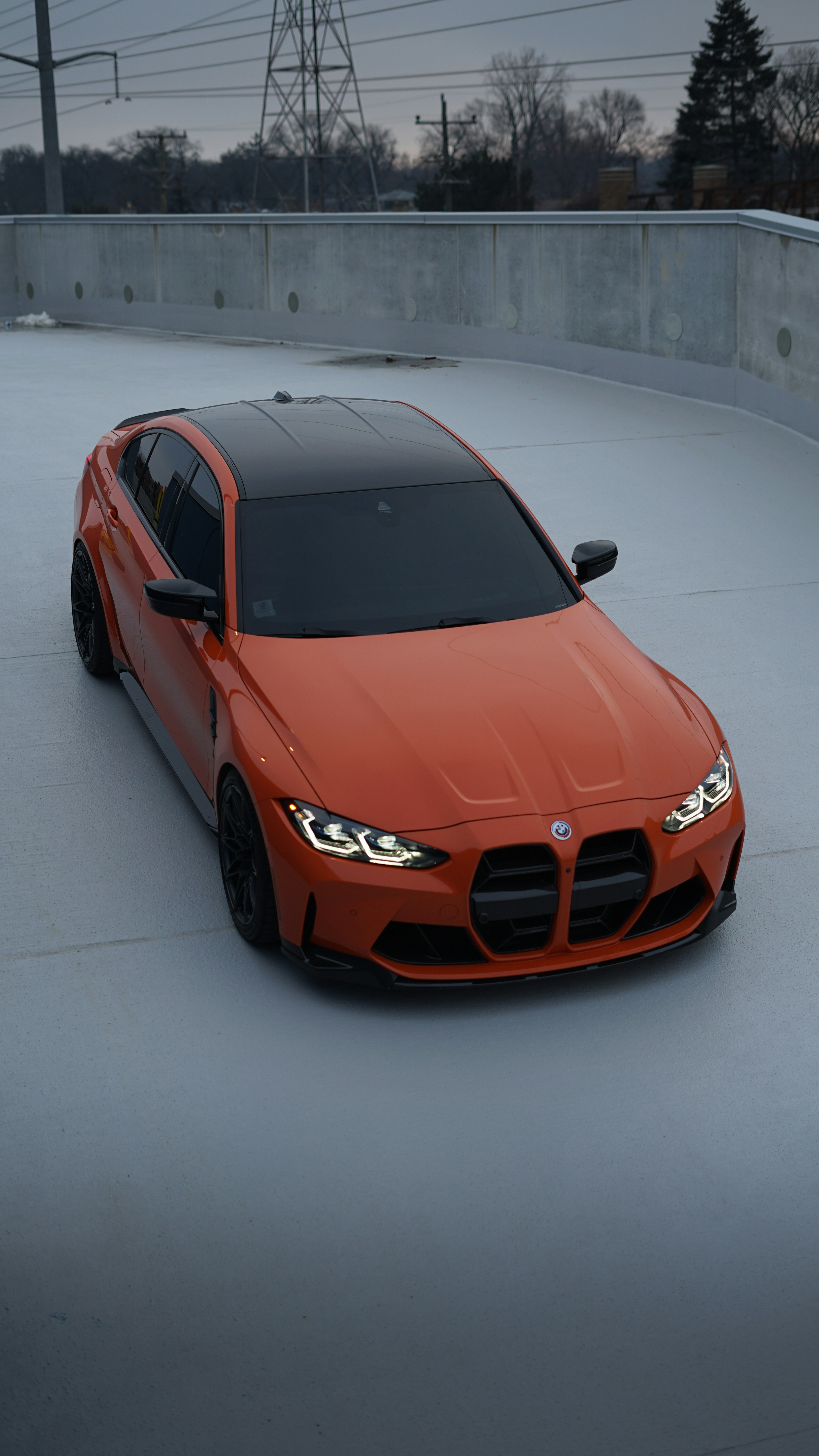 Rooftop Roar: An orange BMW SUV on a desolate rooftop parking deck