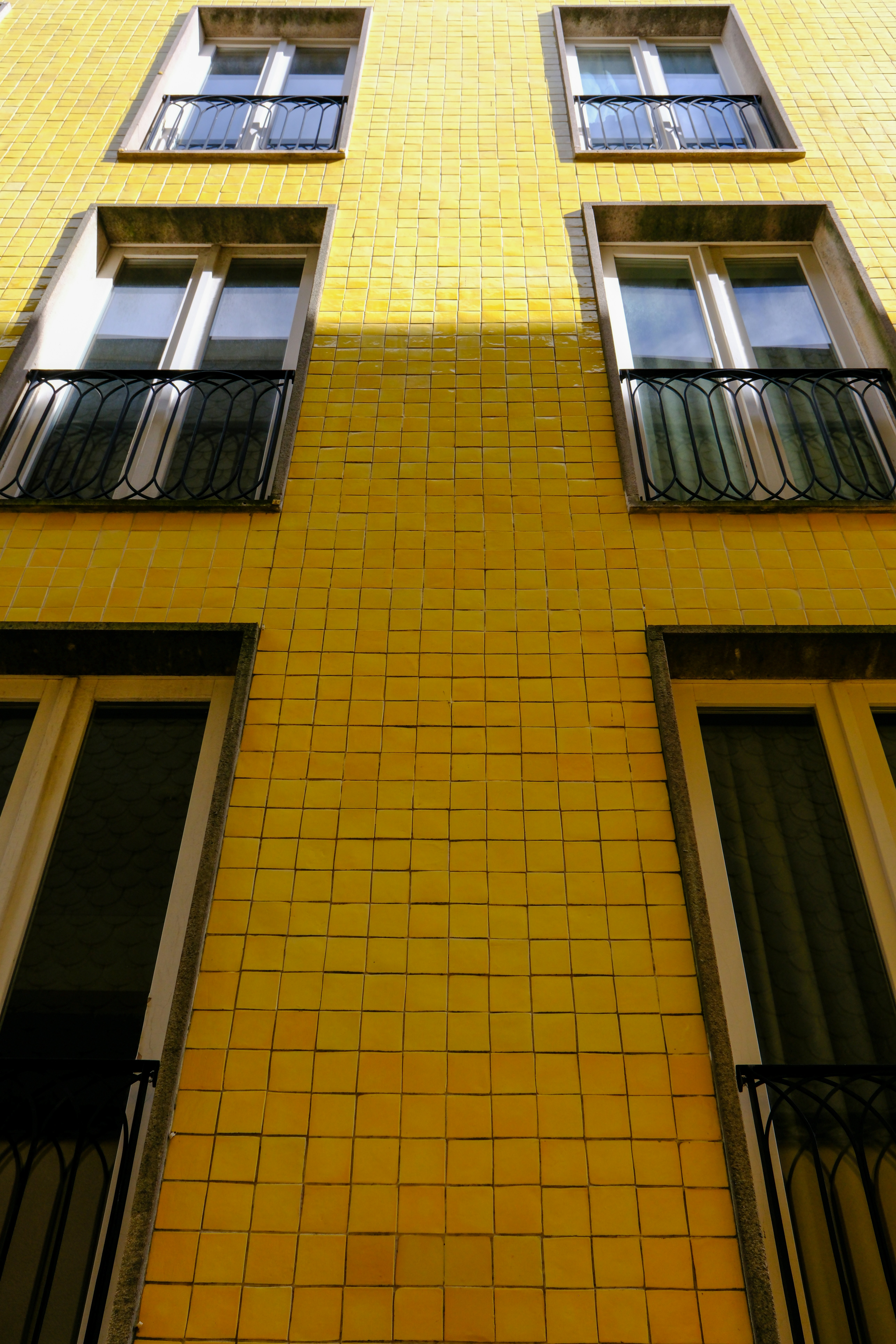 A tall yellow brick building with windows and balconies photo – Free ...