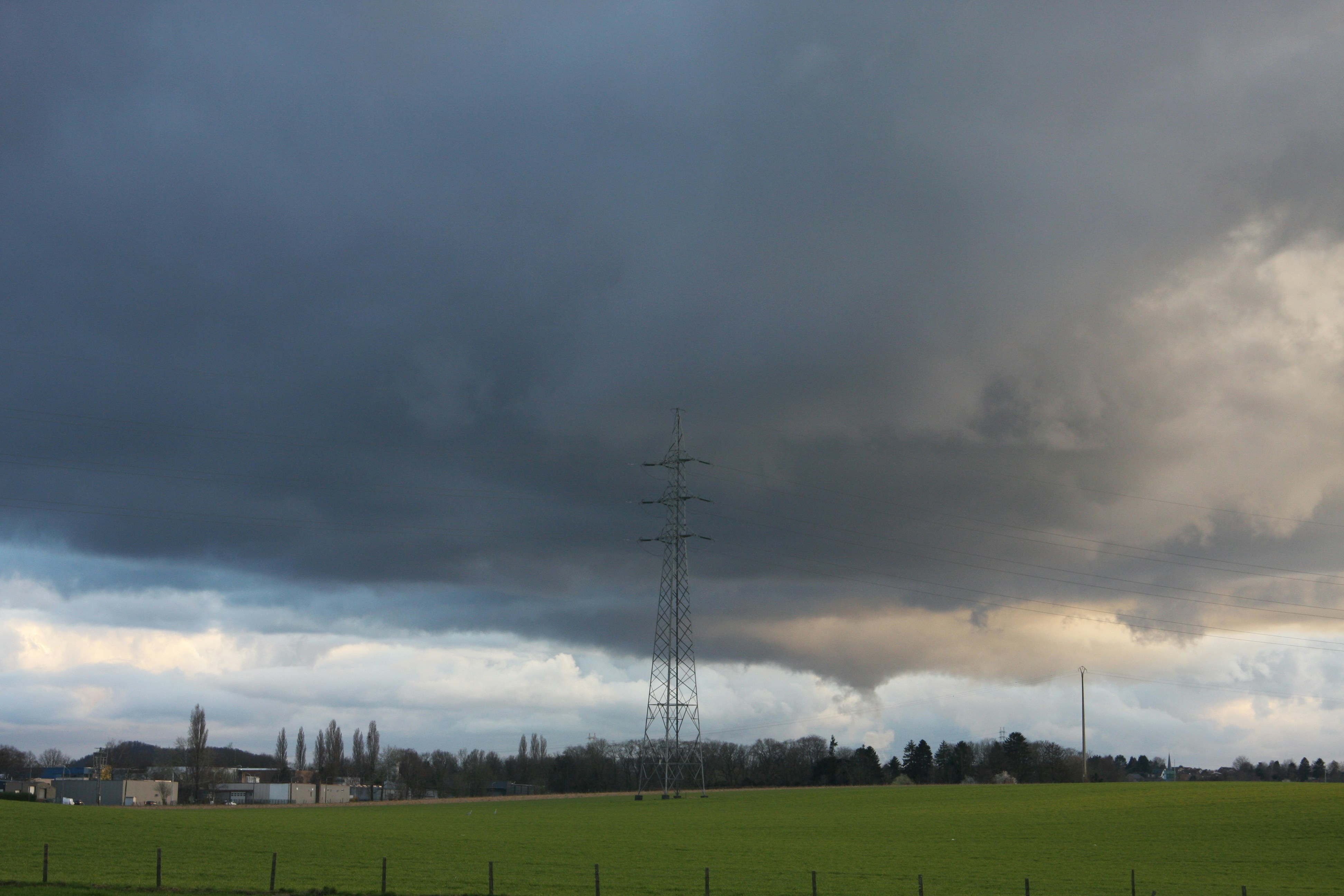 The Steel Sentinel under a Stormy Canopy over a Quiet Green Plain