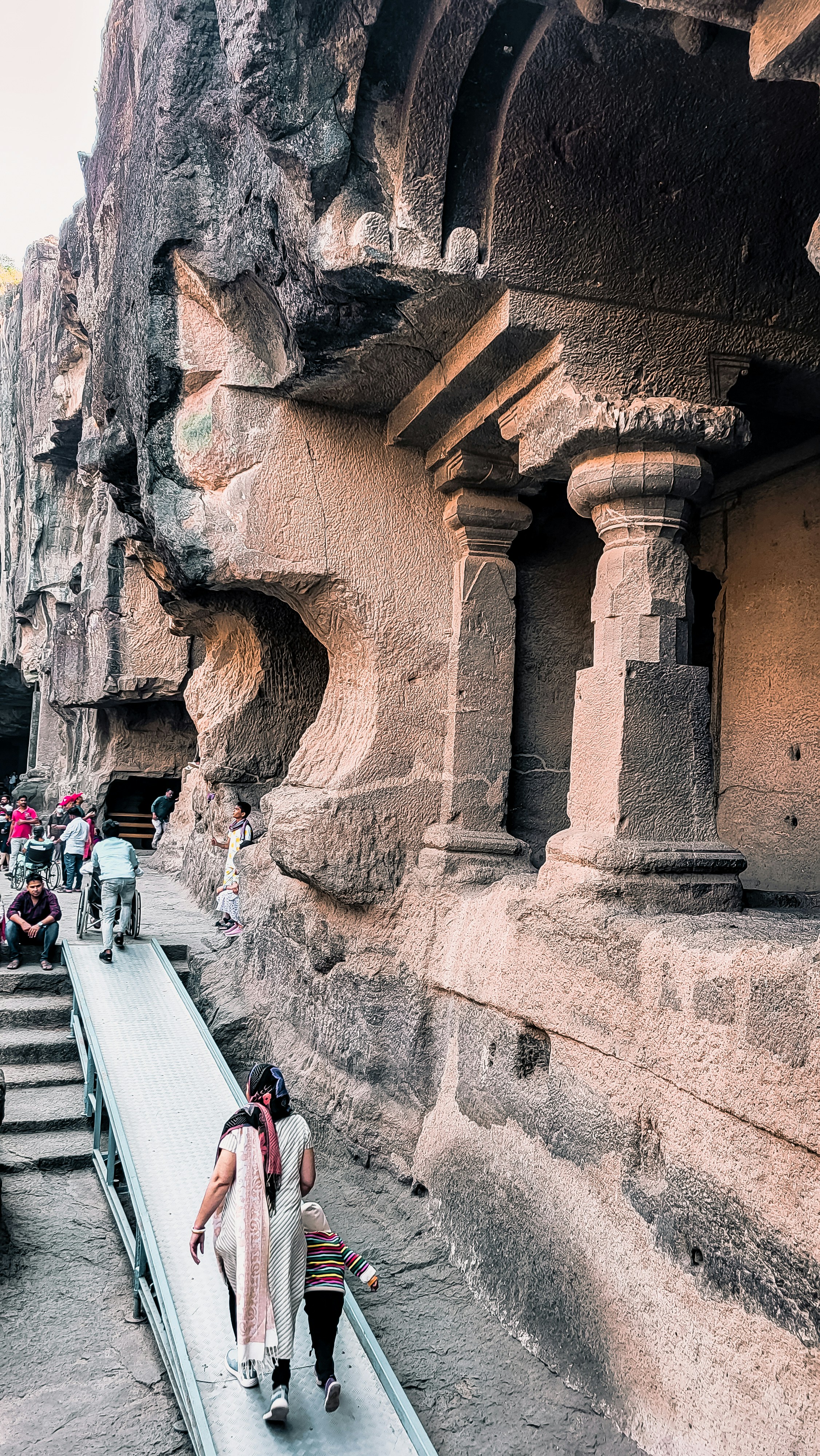 A group of people walking down a walkway next to a cliff photo – Free ...