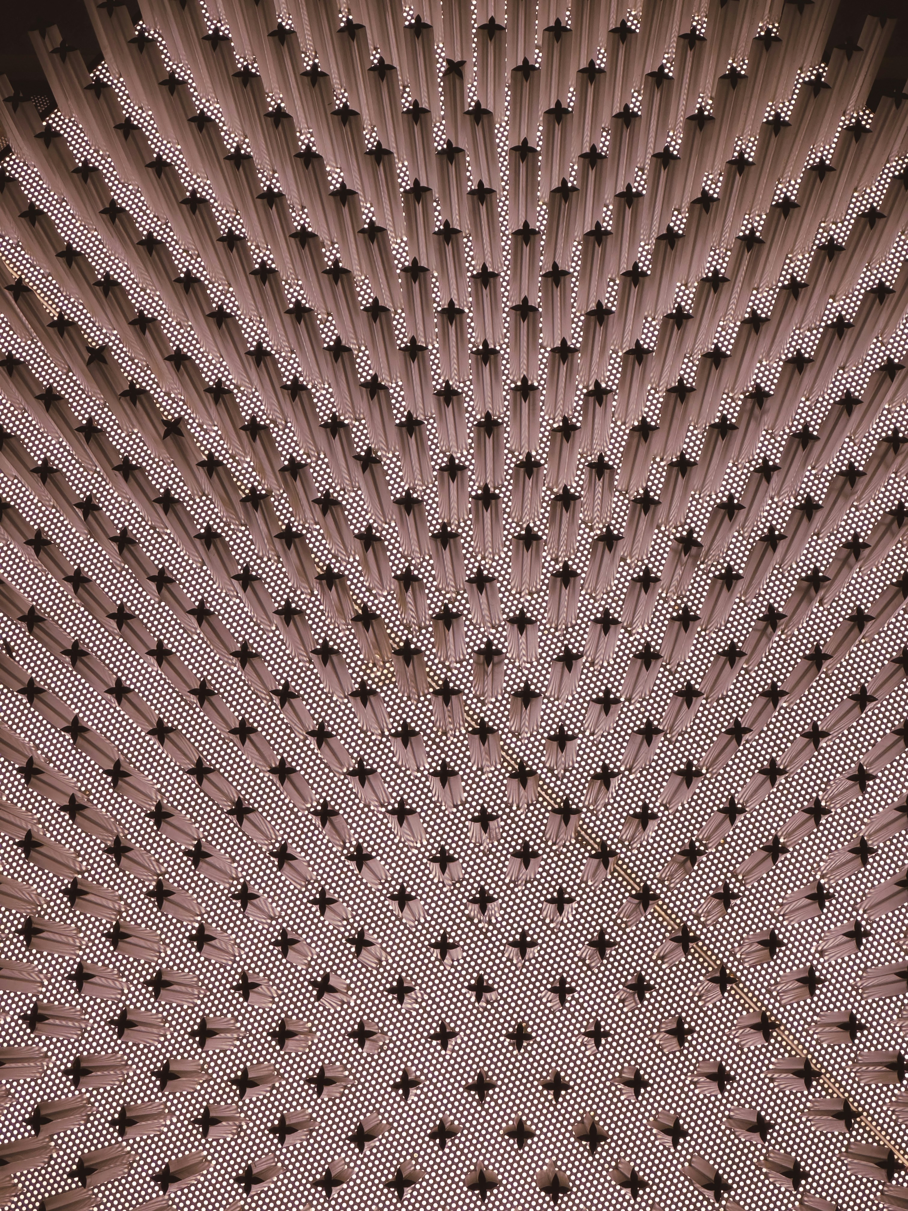 Intricate geometric design of a ceiling featuring a series of repeating triangular and circular elements. The arrangement creates a visually striking pattern.