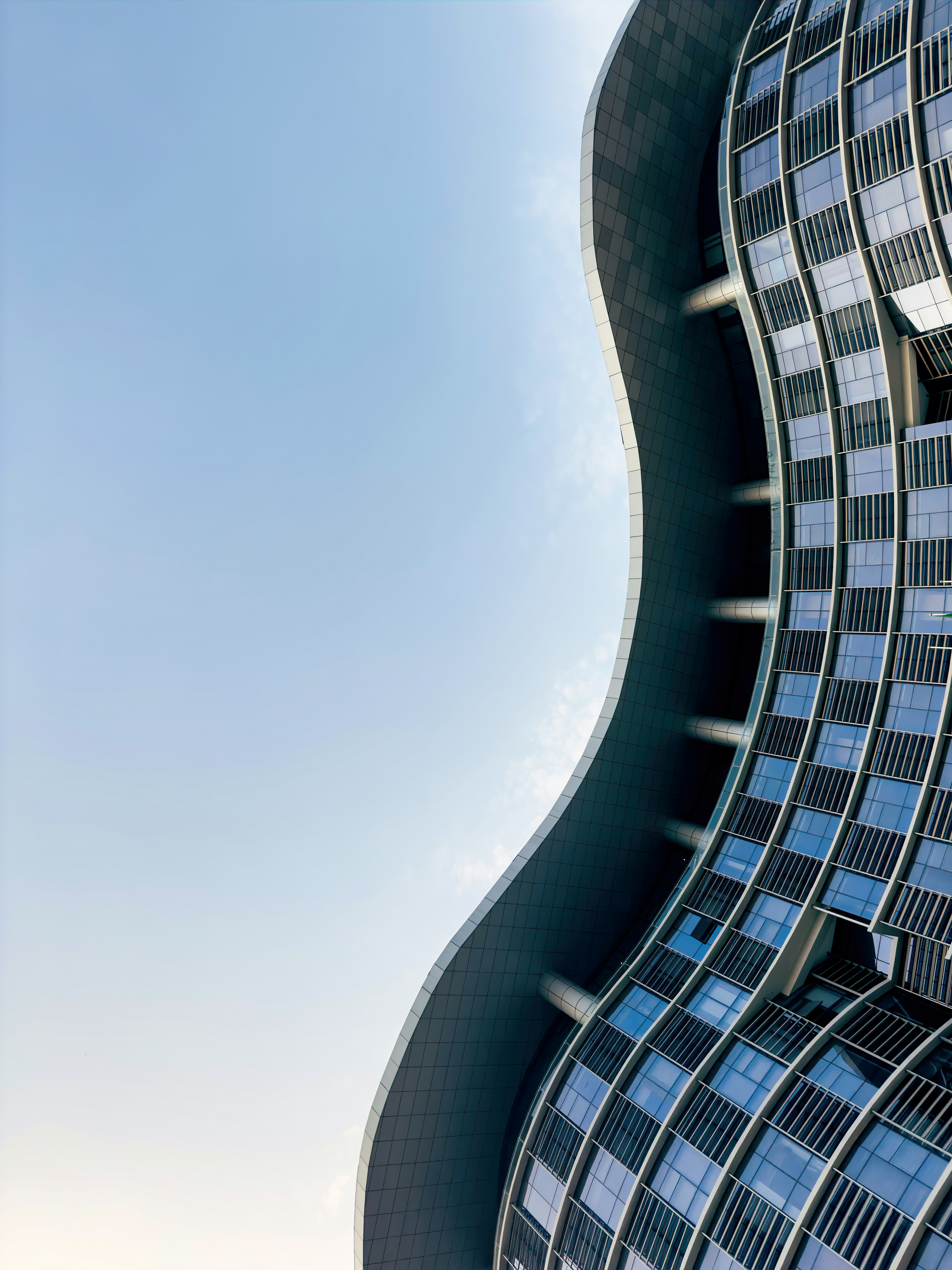 A very tall building with a curved roof photo – Free Blue Image on Unsplash