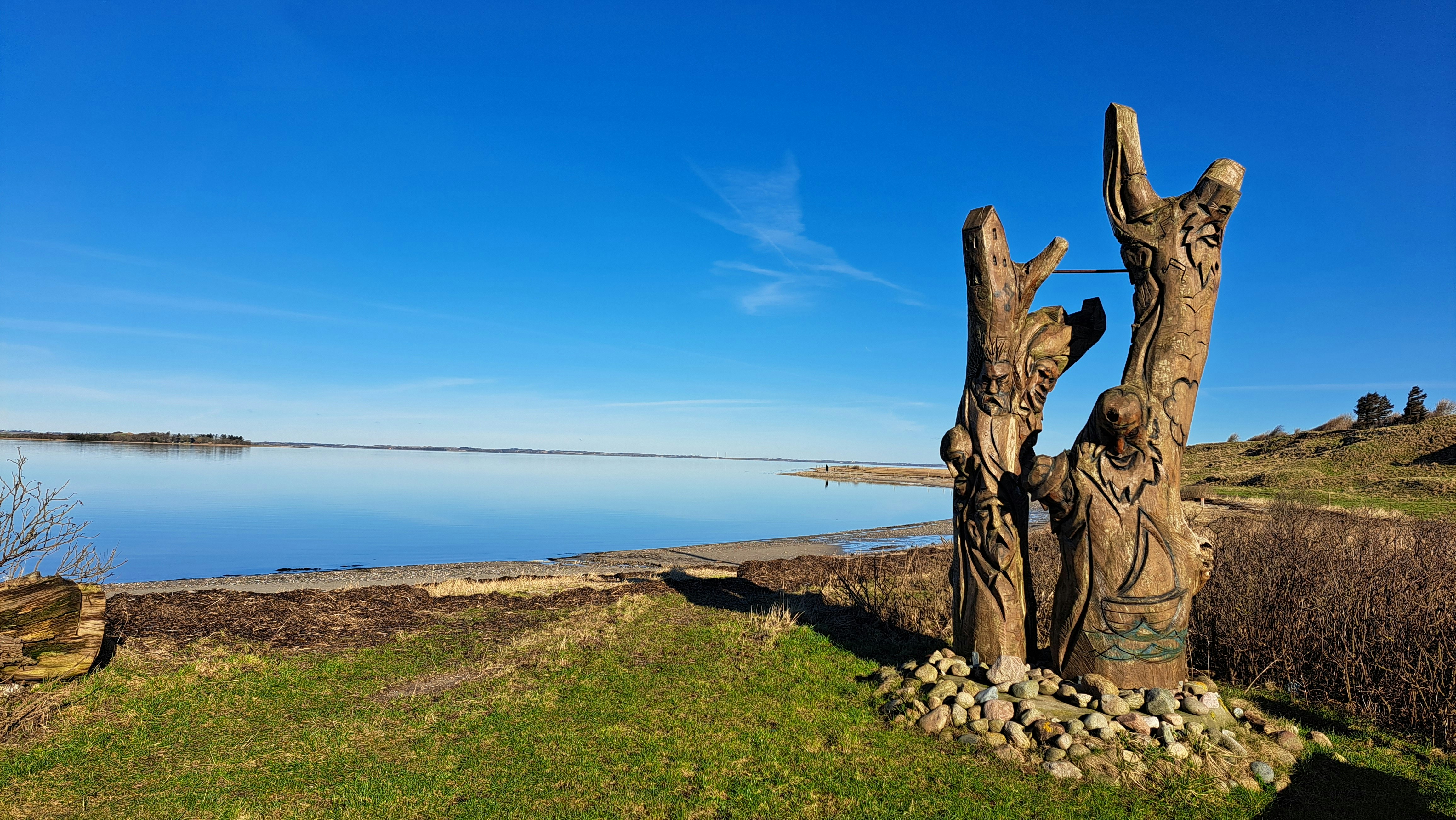 Artwork made from old cut down trees at the harbour by Naessund on the Island of Mors, Denmark. Very beautiful day, blue skies, calm water