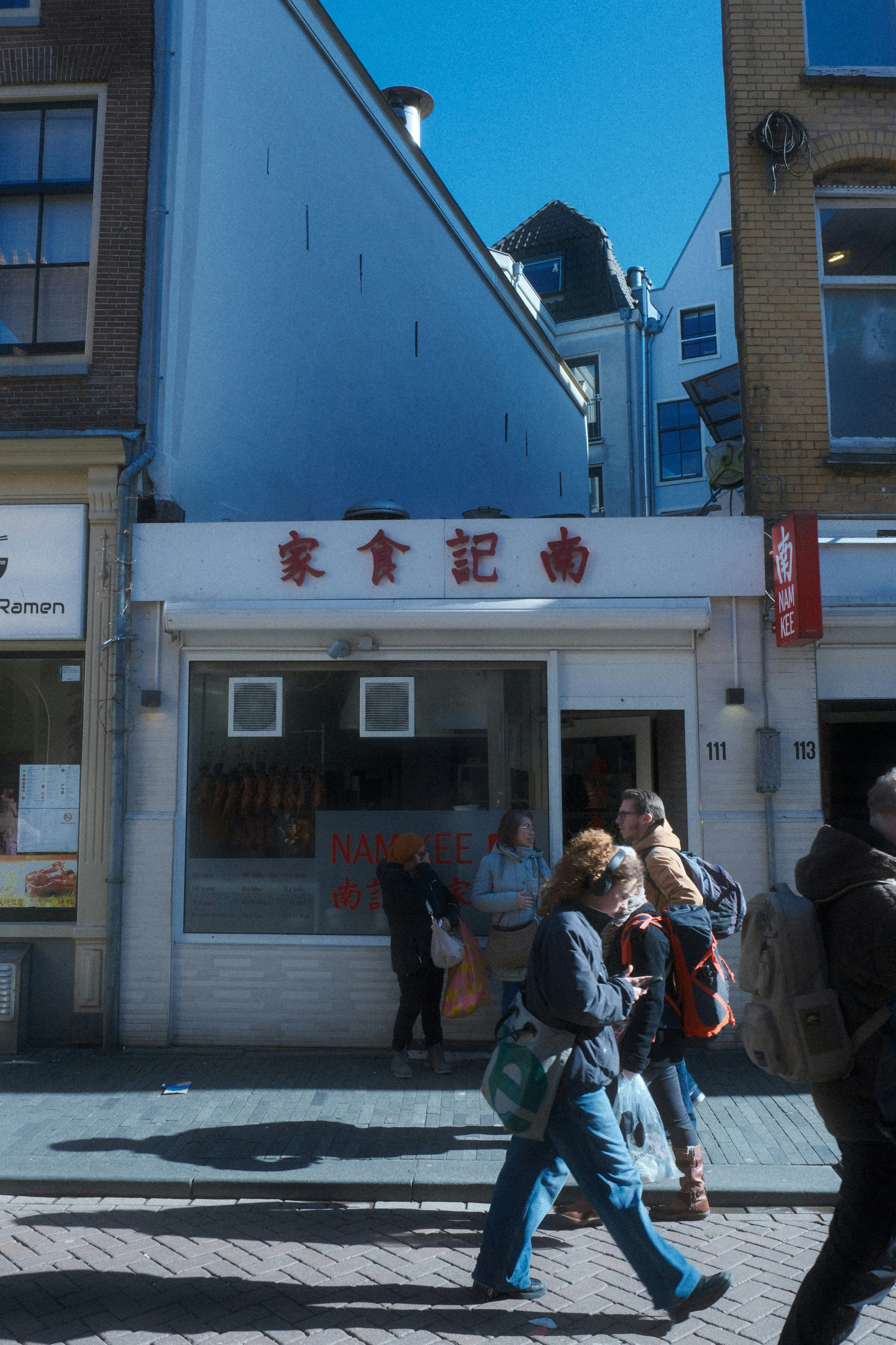 Red Signage Above a Blue-Walled Shopfront on a Busy City Street