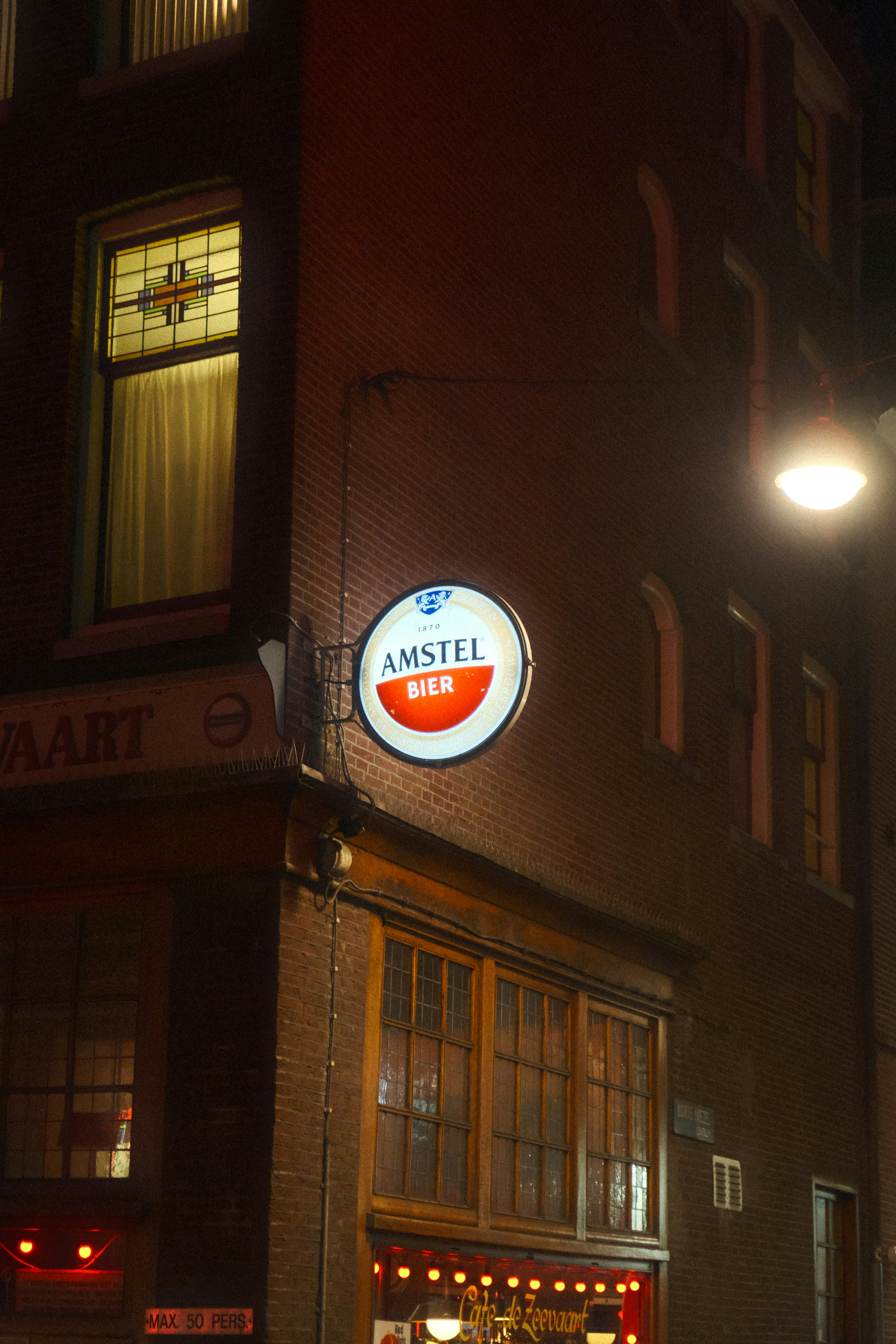 Nightglow: the Amstel Roundel on a Brick-Corner Facade