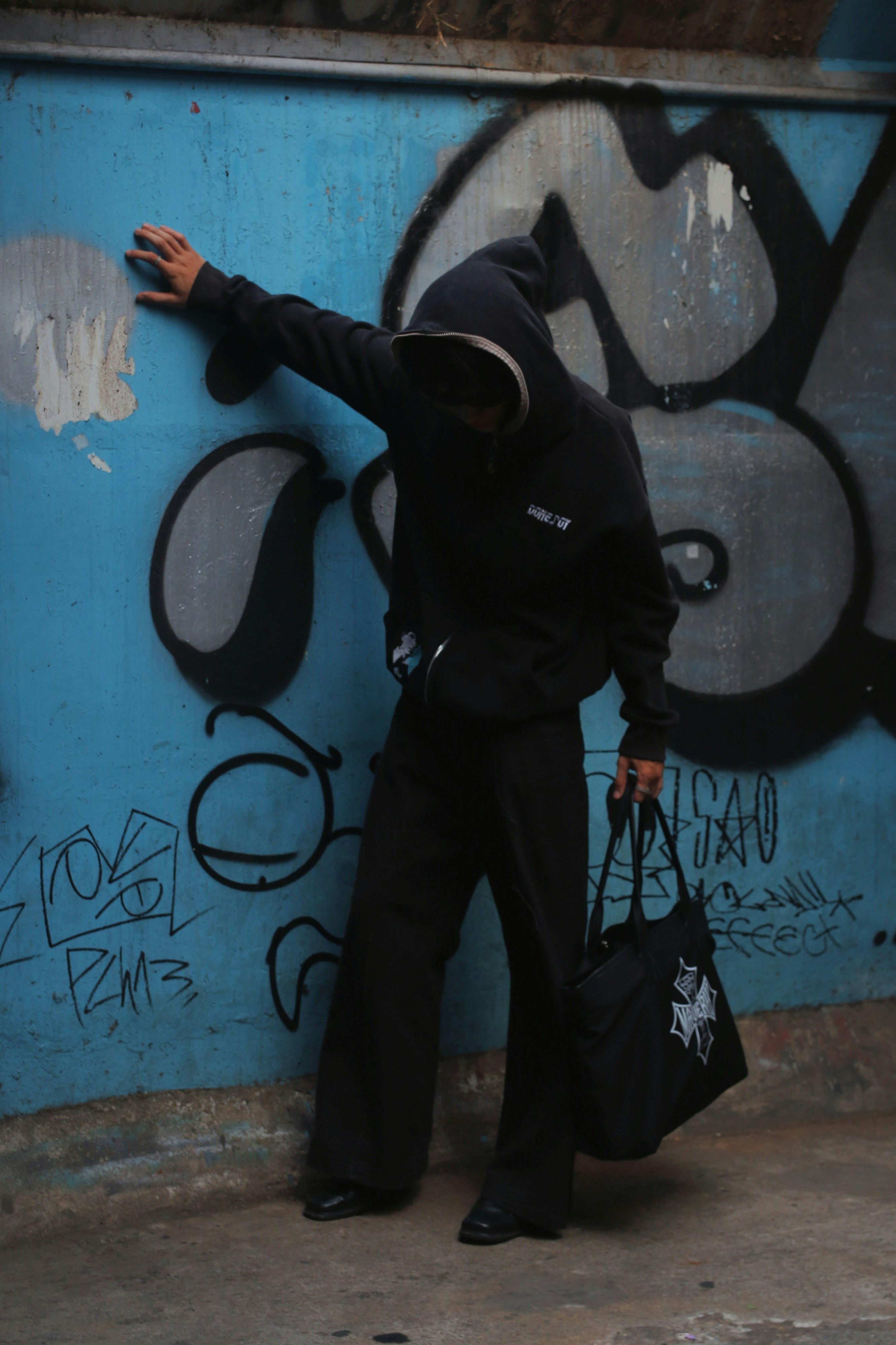 A person leaning against a wall with a bag photo – Free Adult Image on ...