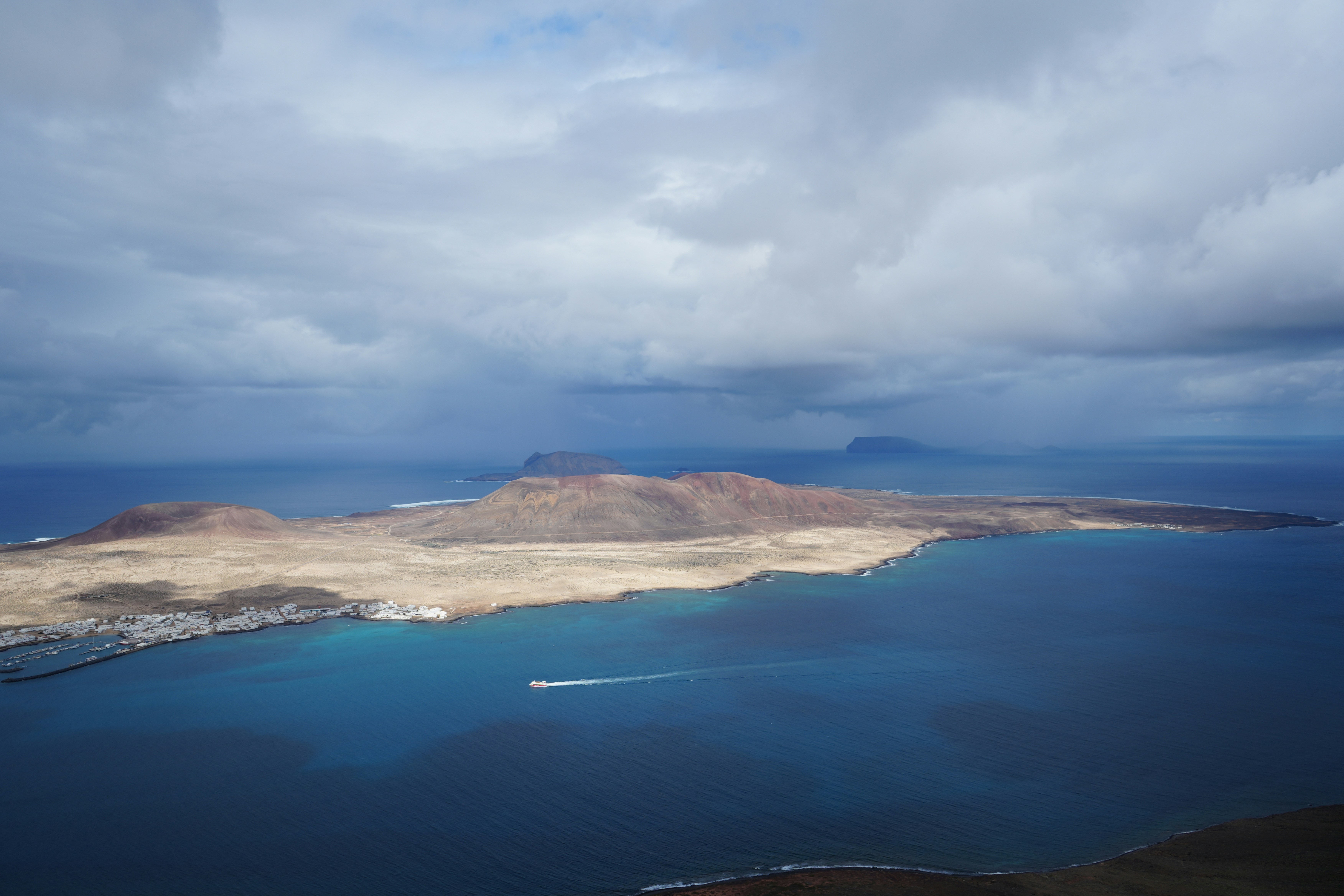 An island in the middle of the ocean under a cloudy sky photo – Free ...