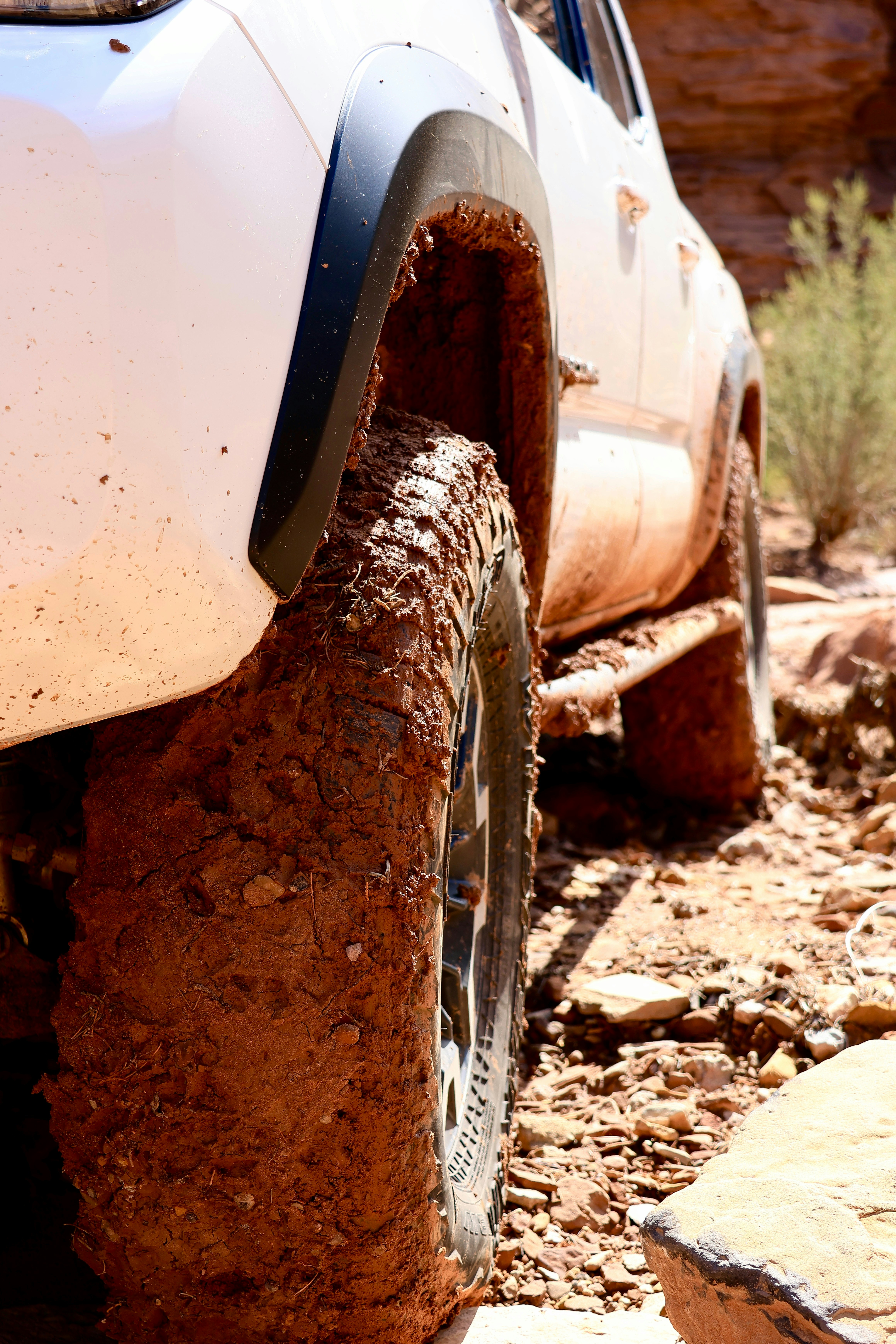 Desert Grip: Mud-Caked Tire Clawing Through Red Dirt