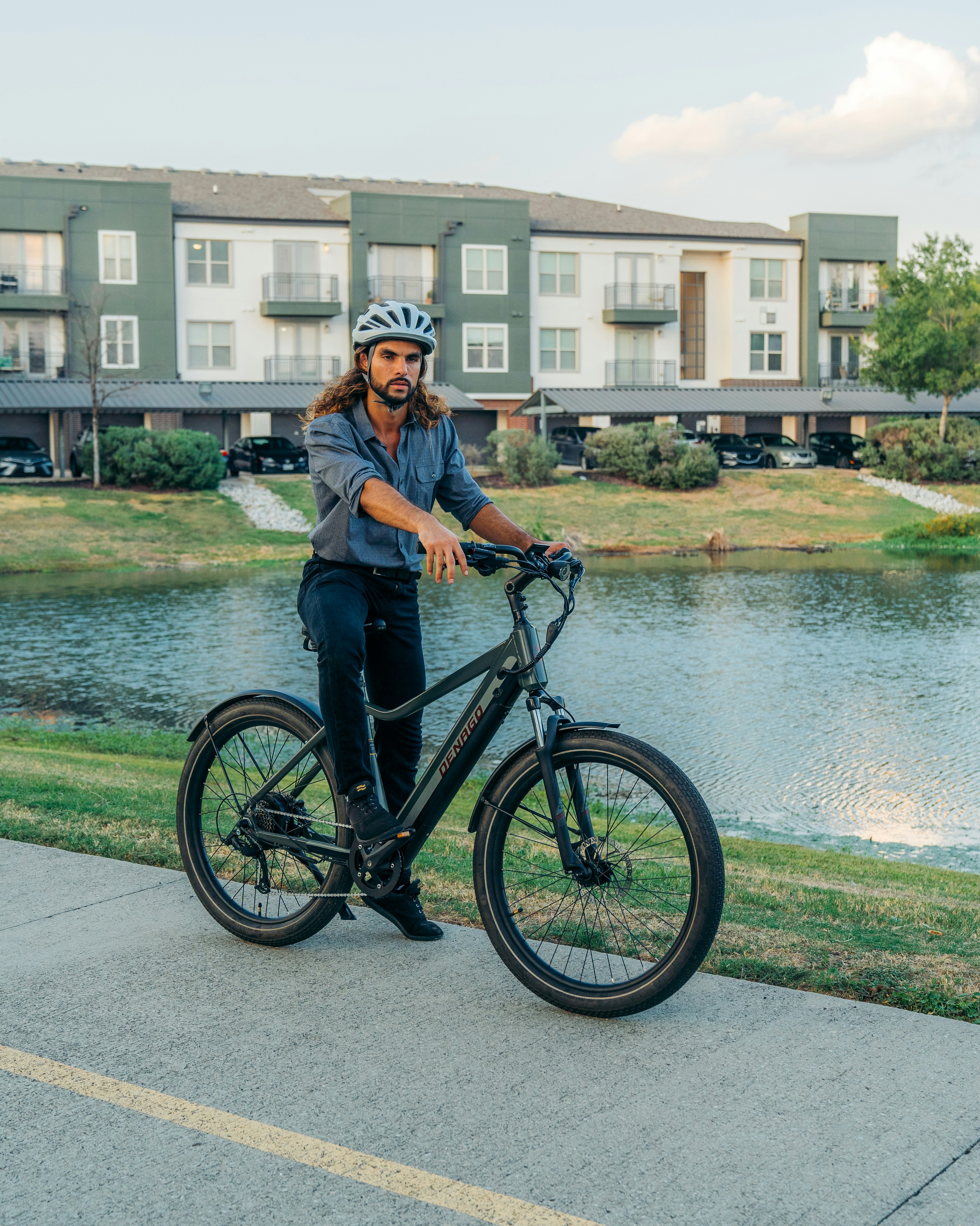 A man riding a bike down a sidewalk next to a lake photo – Free Freedom ...