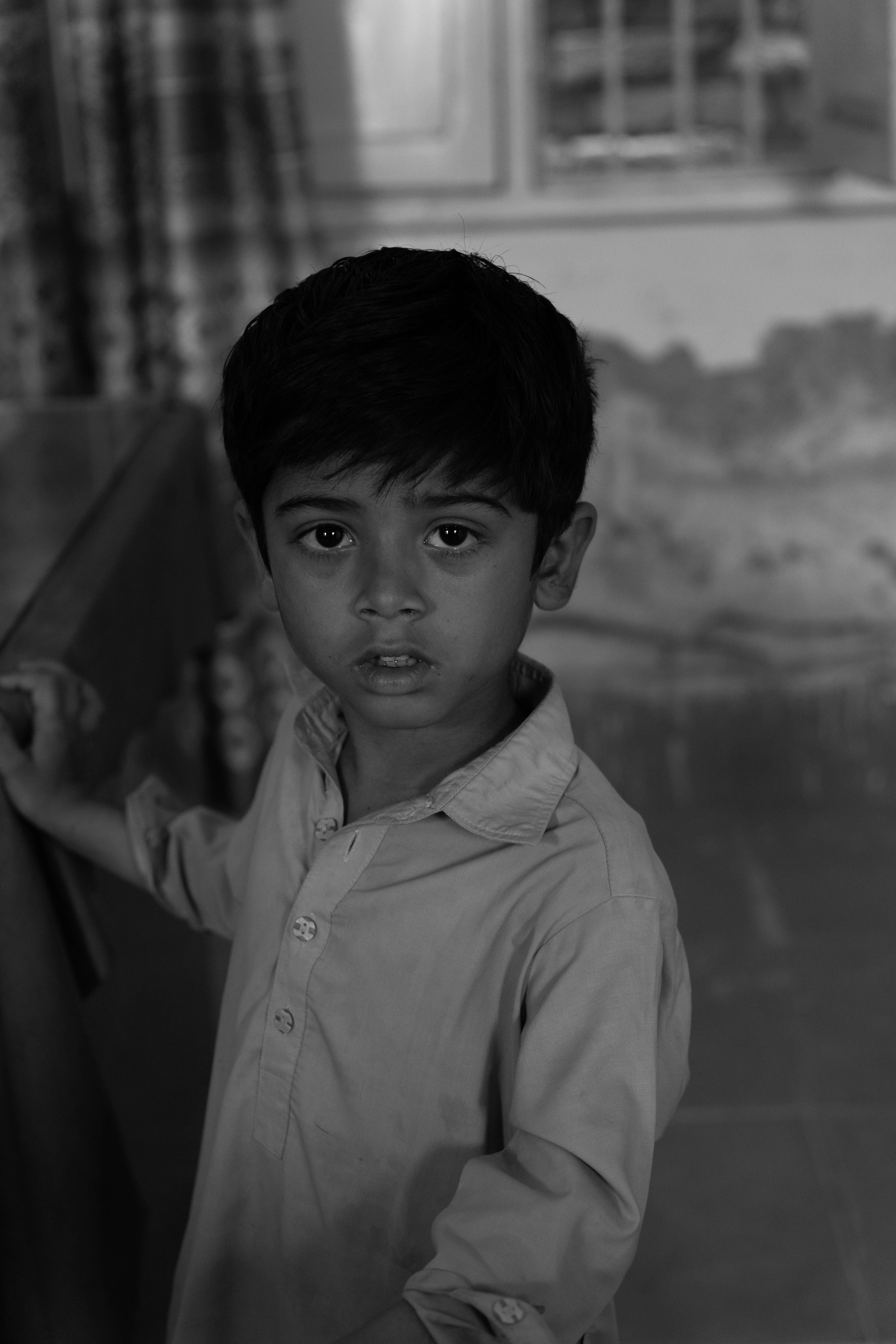 A young boy standing in front of a window photo – Free Grey Image on ...