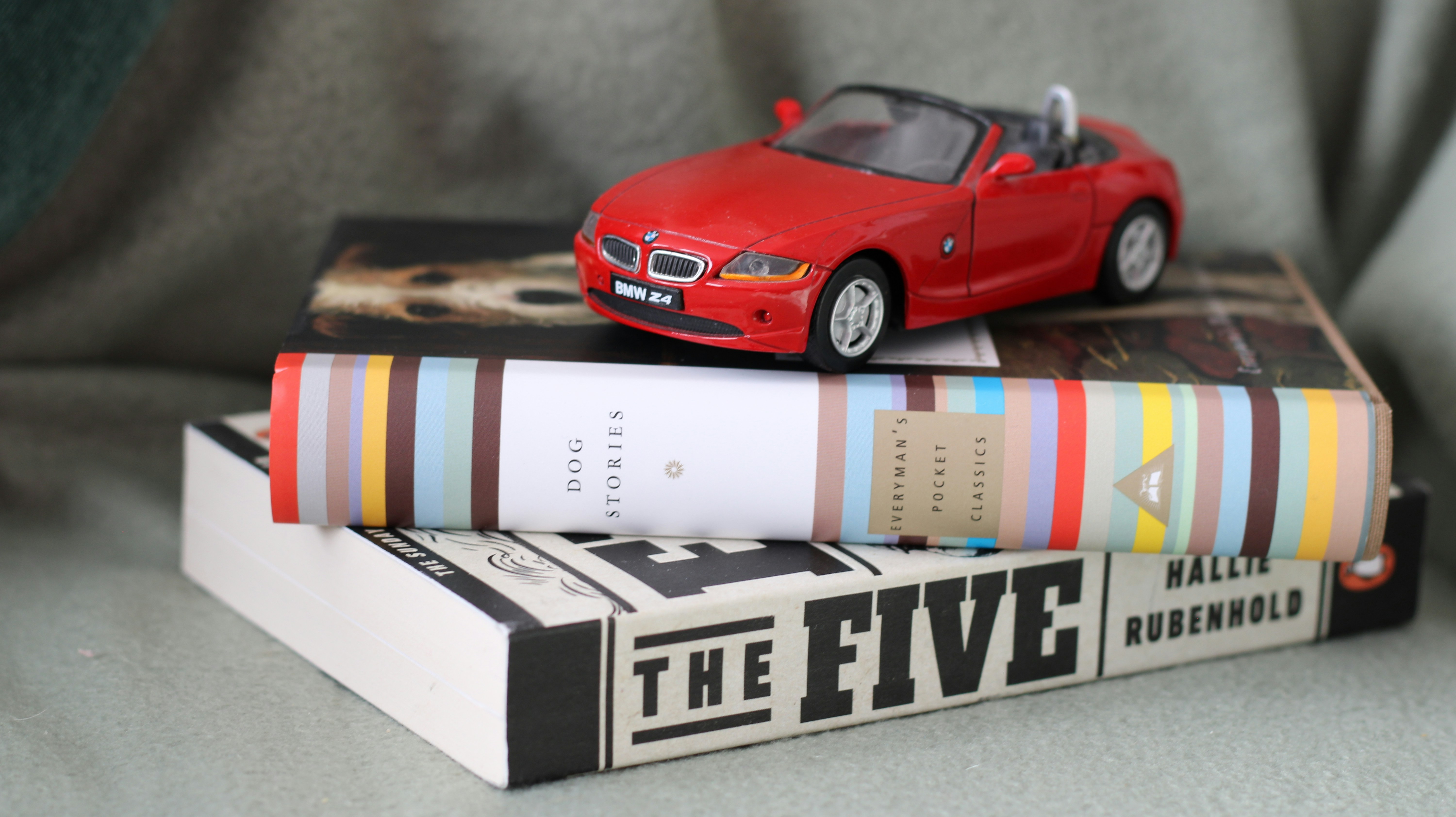 Miniature red convertible perched above a stack of colorful book spines