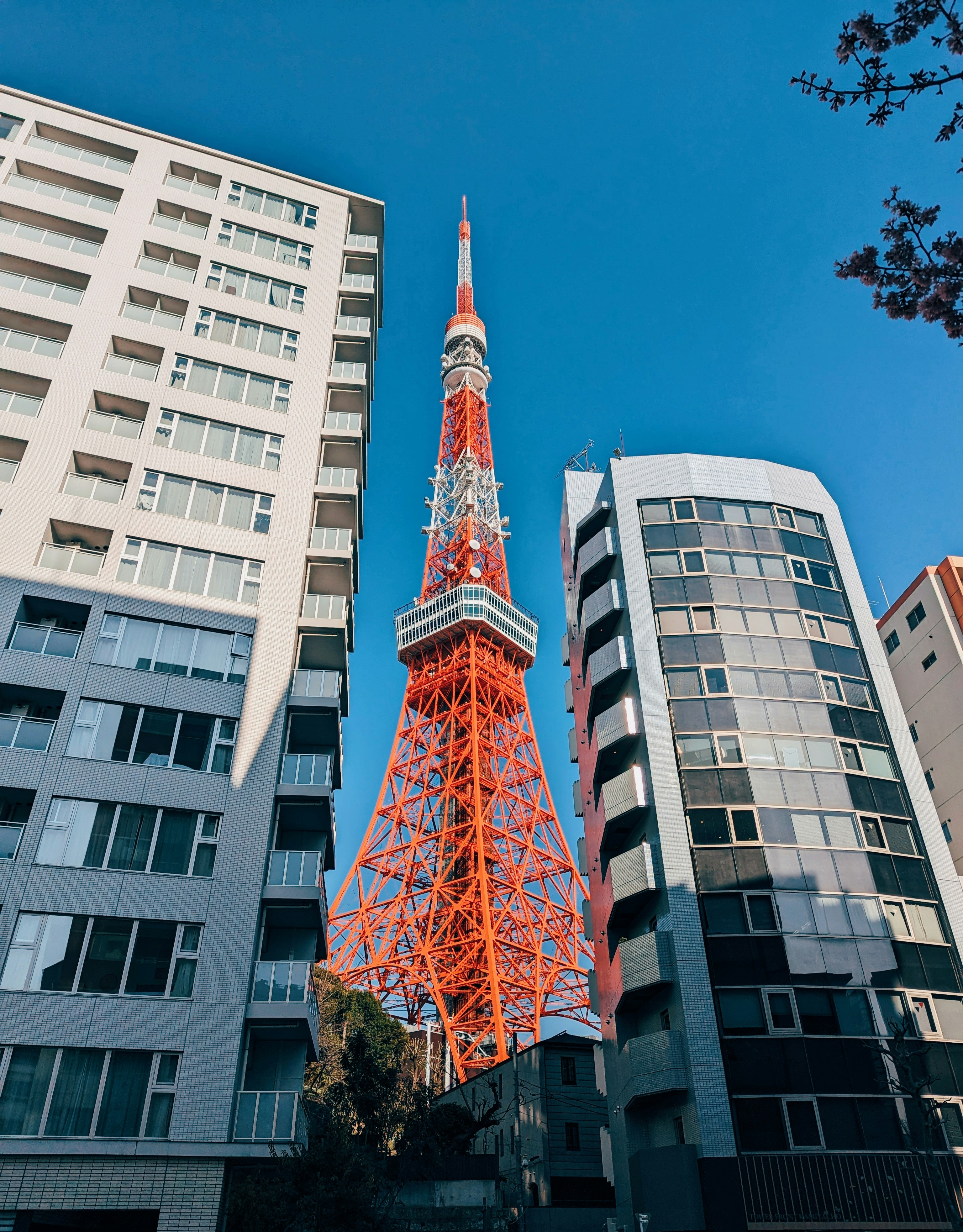 A very tall red tower in the middle of some buildings photo – Free ...