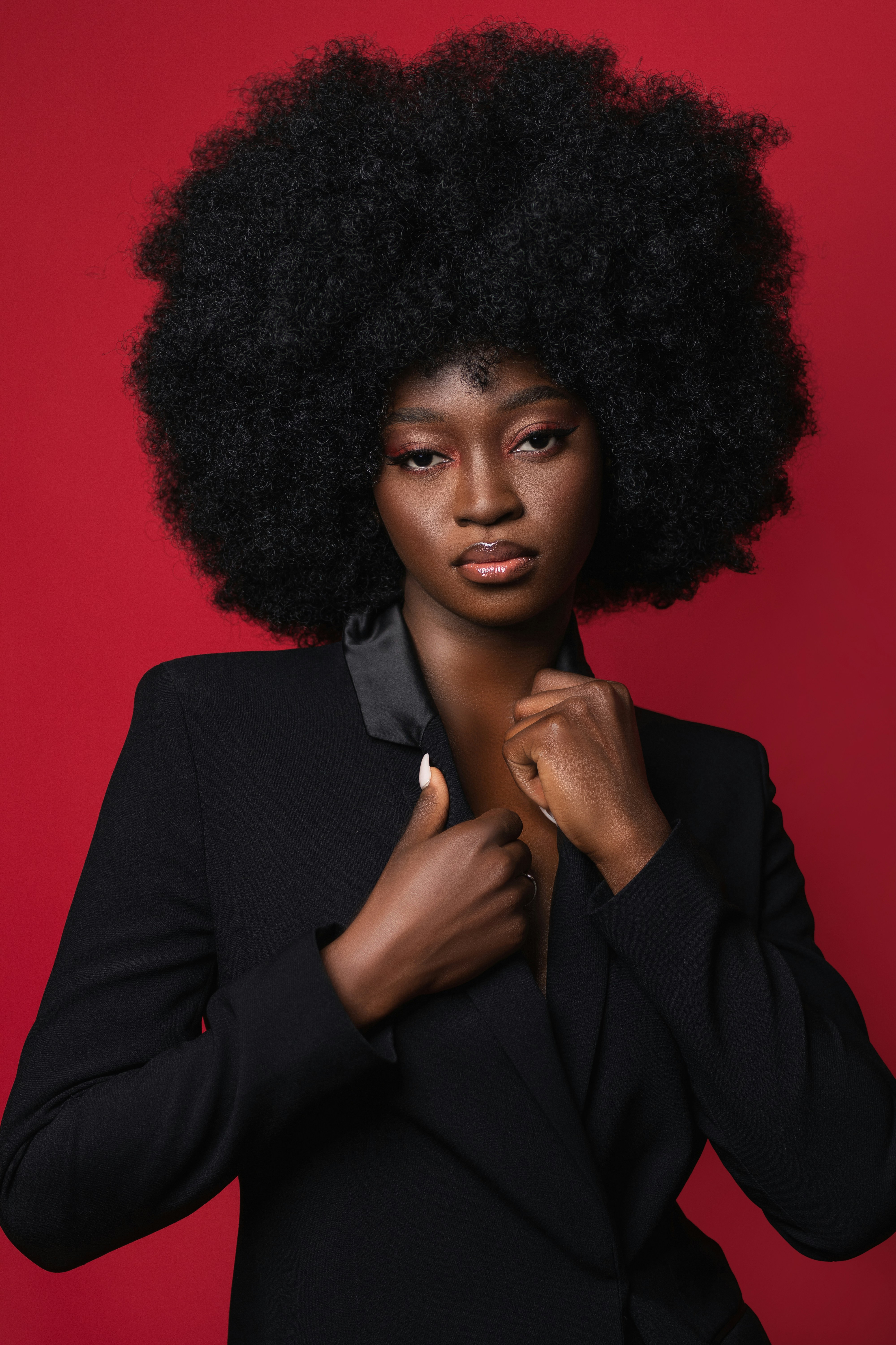 A woman with an afro standing in front of a red background photo – Free ...
