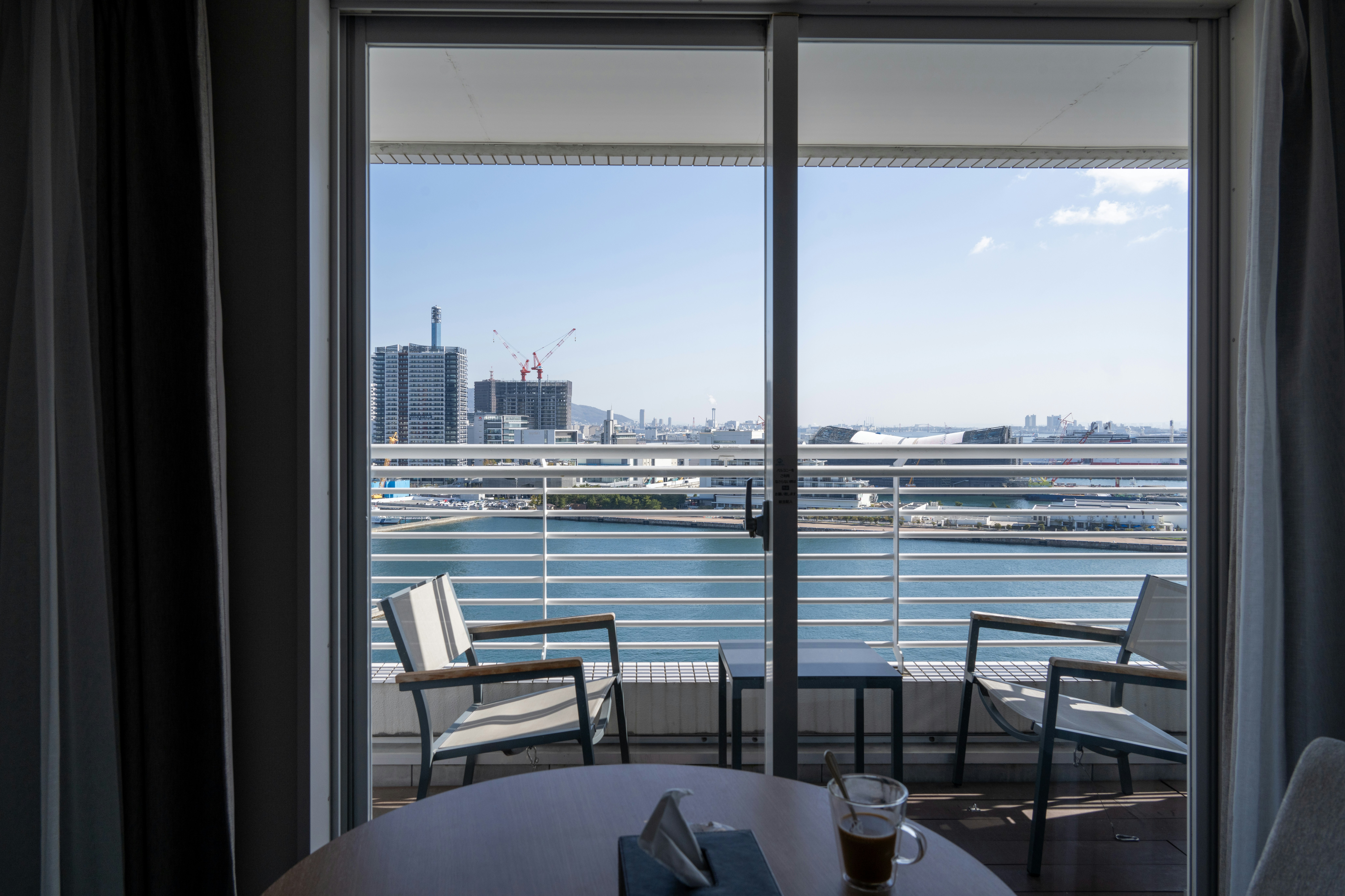 A balcony with a table and chairs overlooking a body of water photo ...