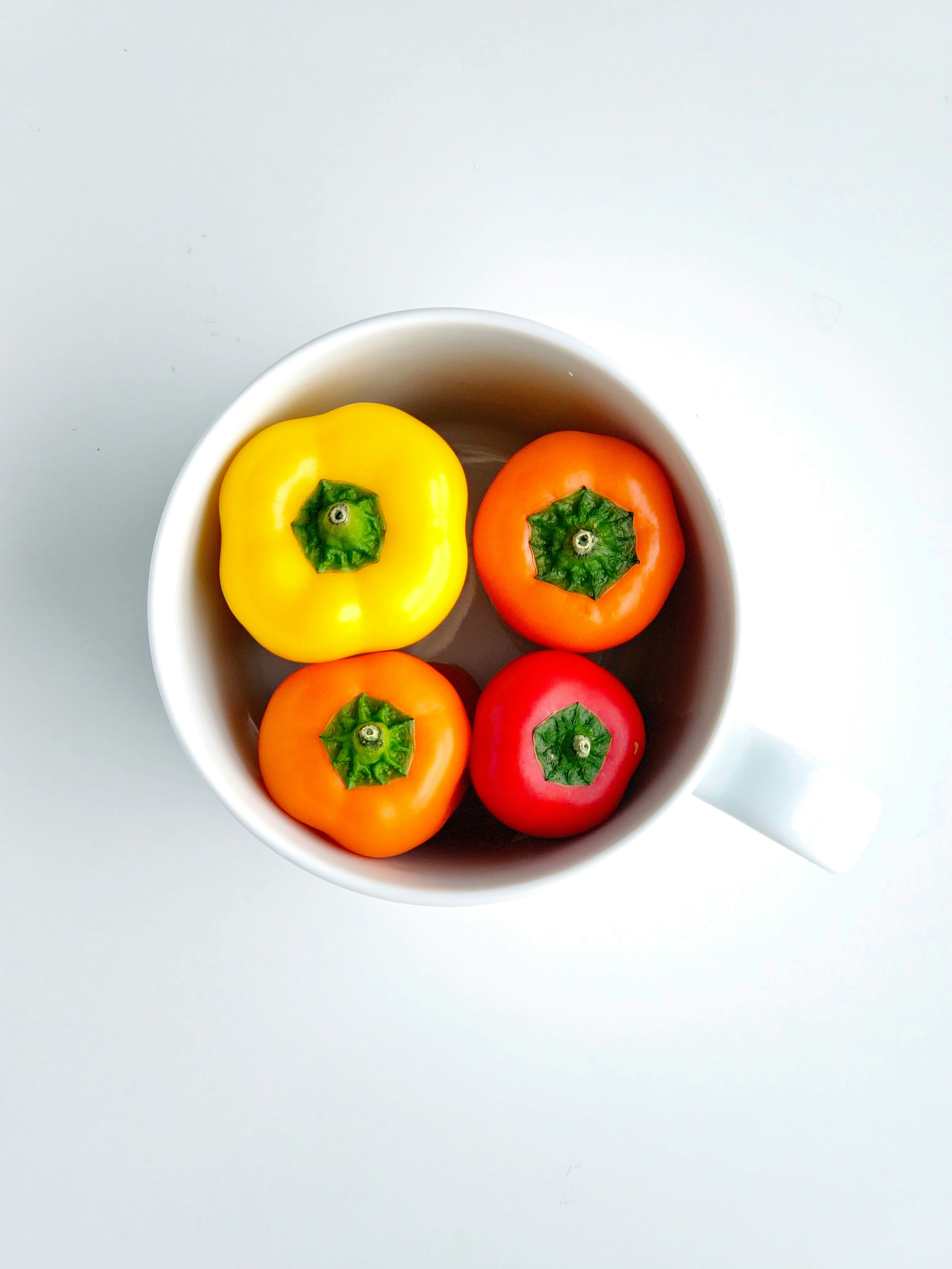 A cup filled with different colored peppers on top of a table photo ...