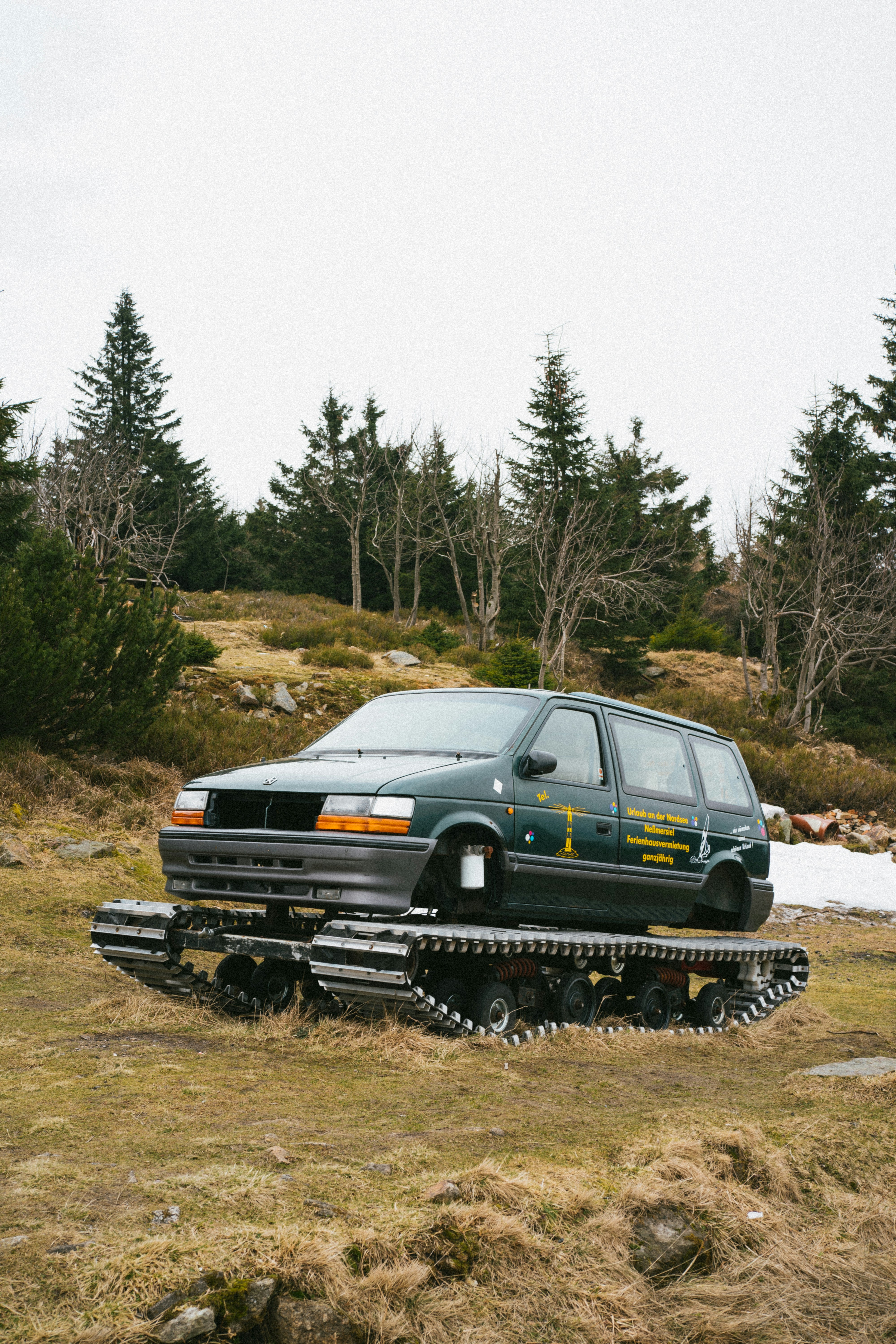 Green Minivan on Tank Tracks Traverses a Rocky Field