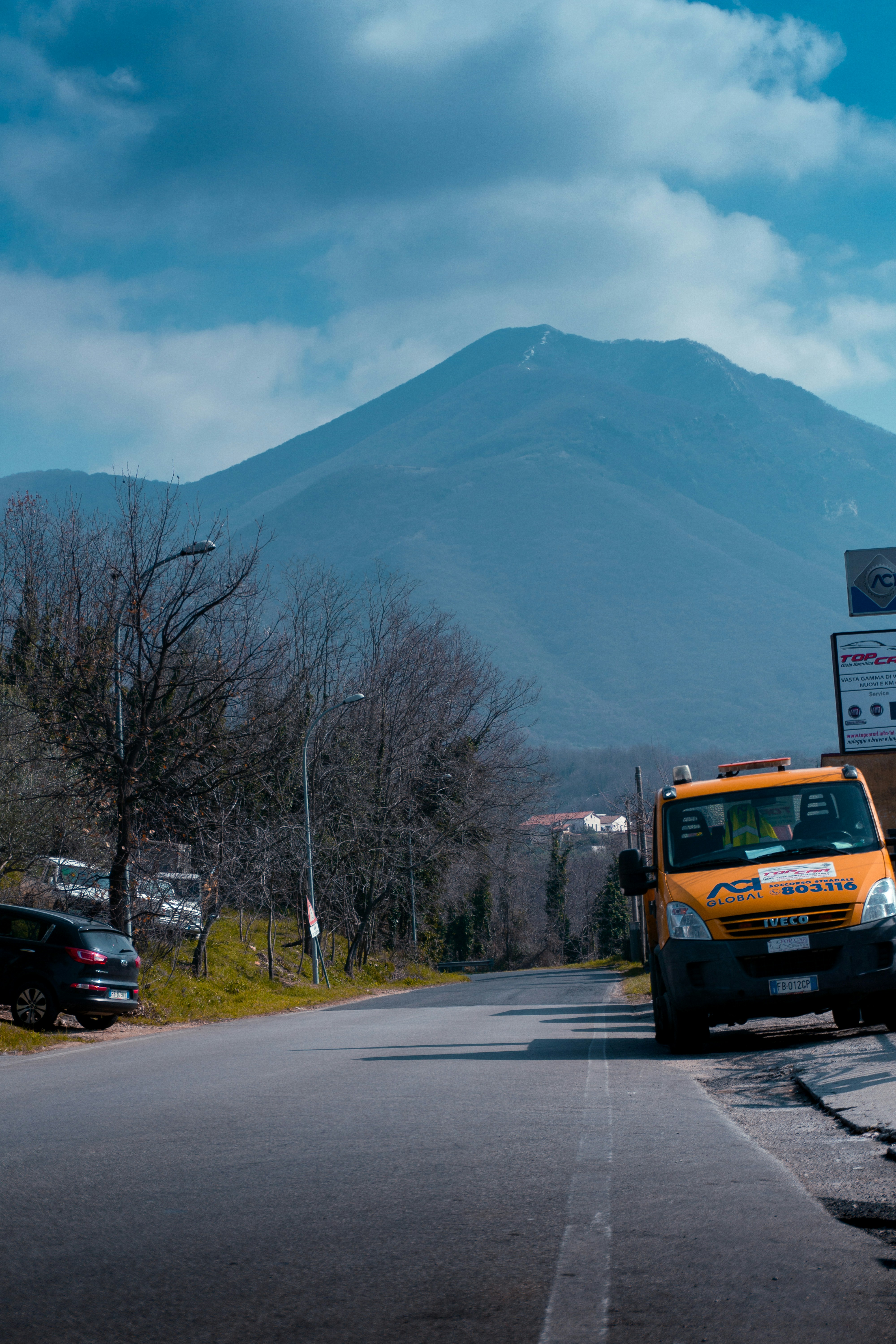 Orange Tow Truck Guards a Quiet Mountain Road Under a Blue Sky