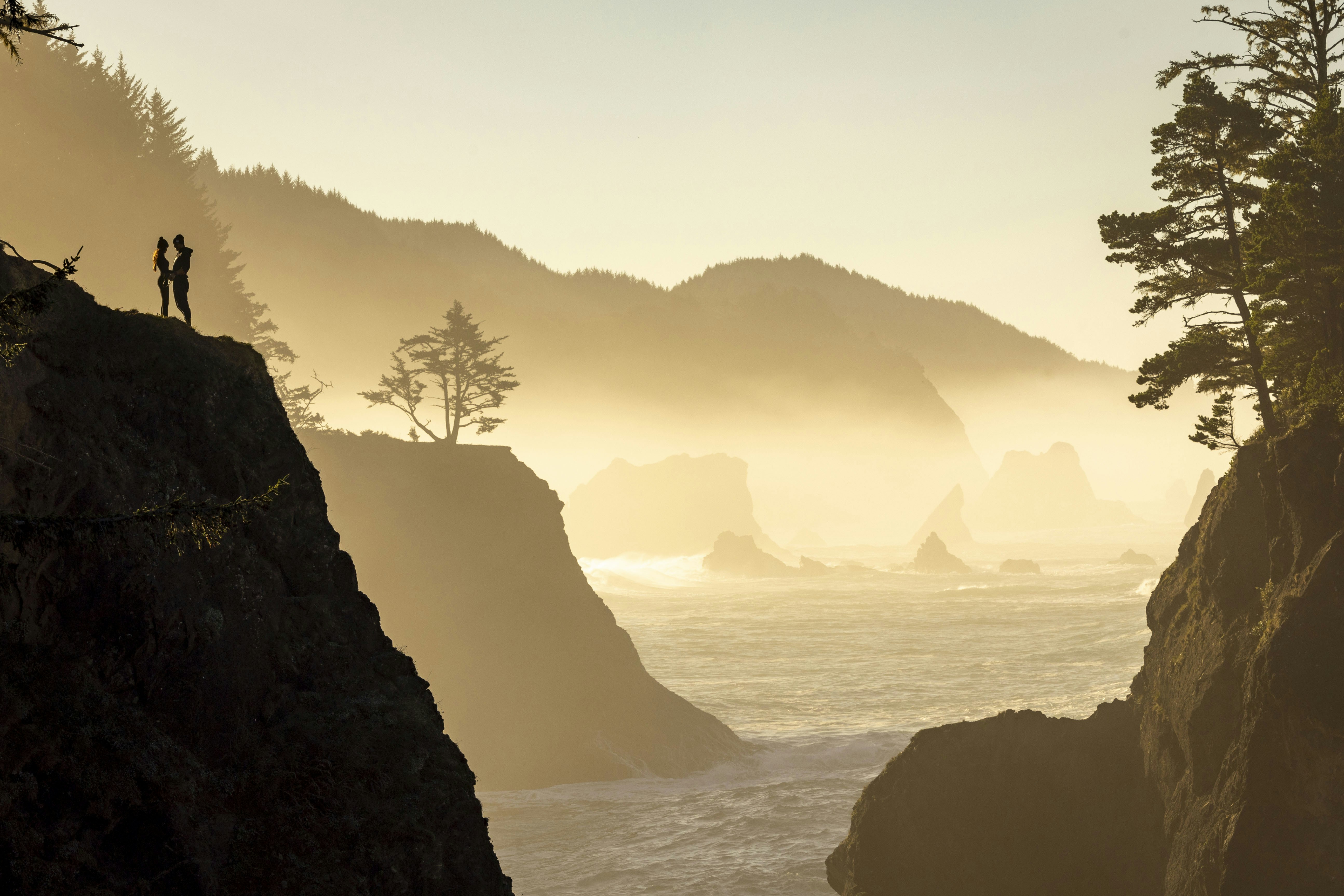 A couple of people standing on top of a cliff photo – Free Cliff Image ...