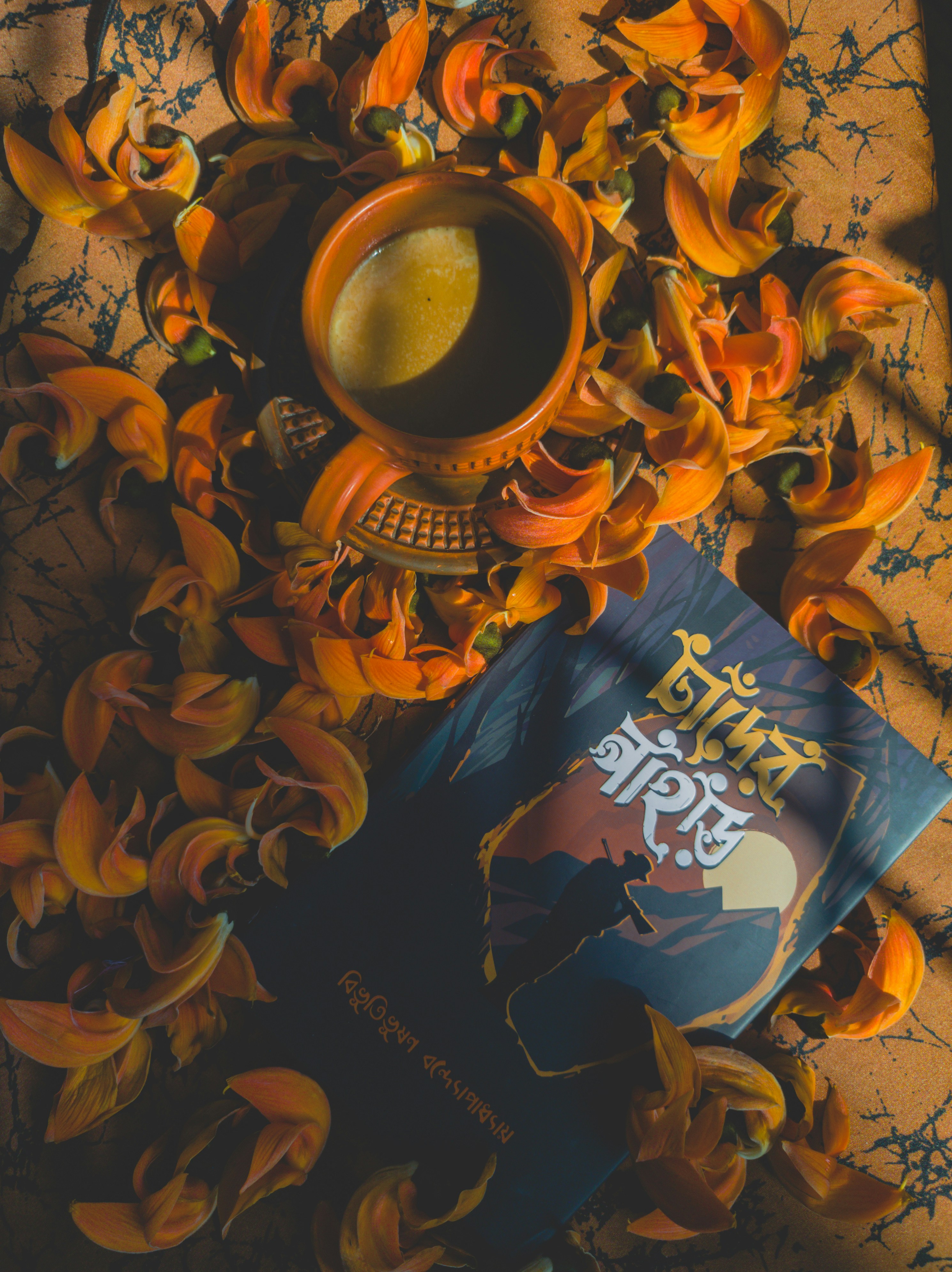 Autumn ritual: coffee cup amid orange petals and a mystic book