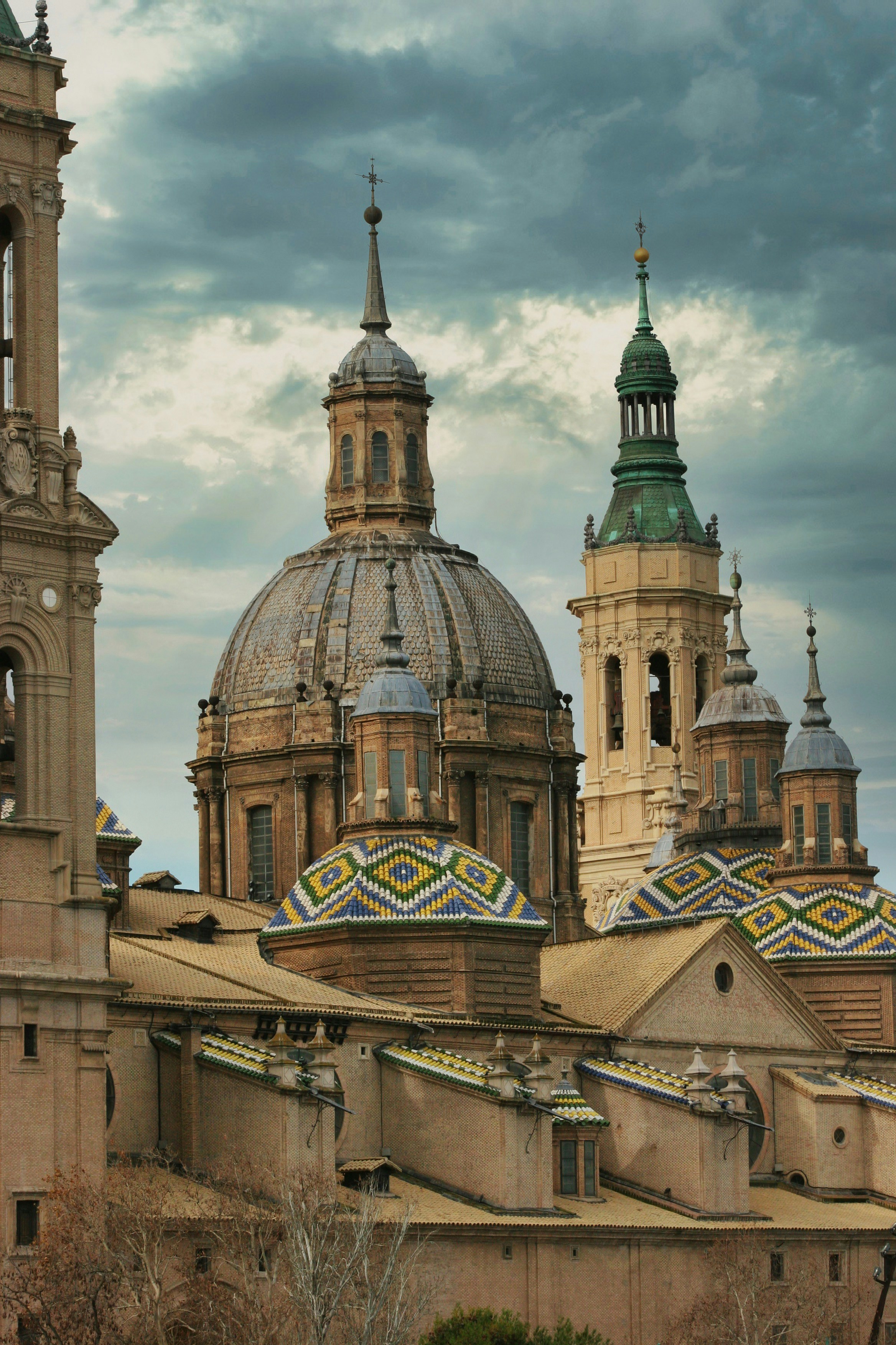 Intricate domes and spires of a historic building rise against a dramatic sky, showcasing architectural elegance and detail.