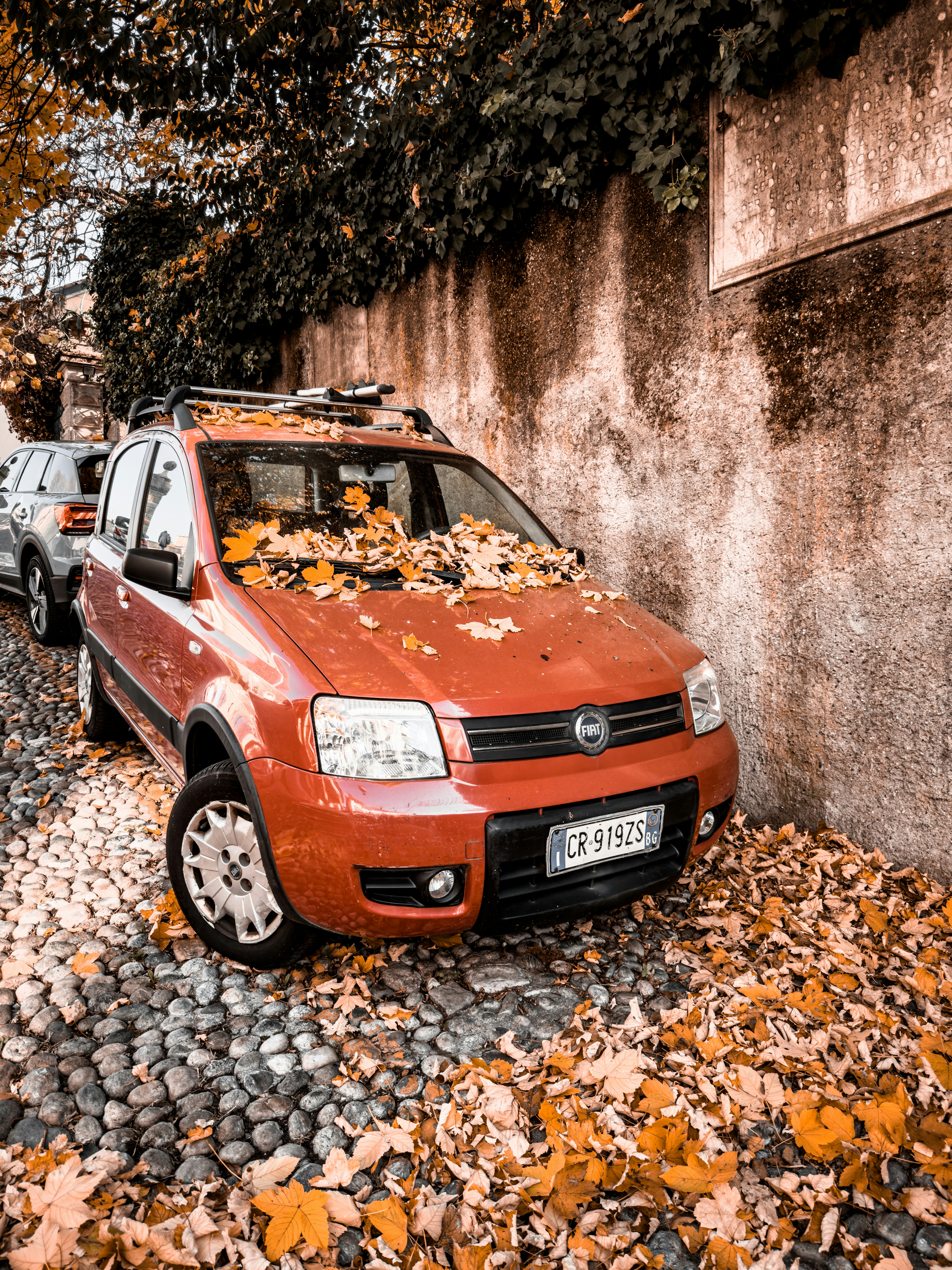 Crimson Fiat Among Autumn Leaves on a Cobblestone Lane