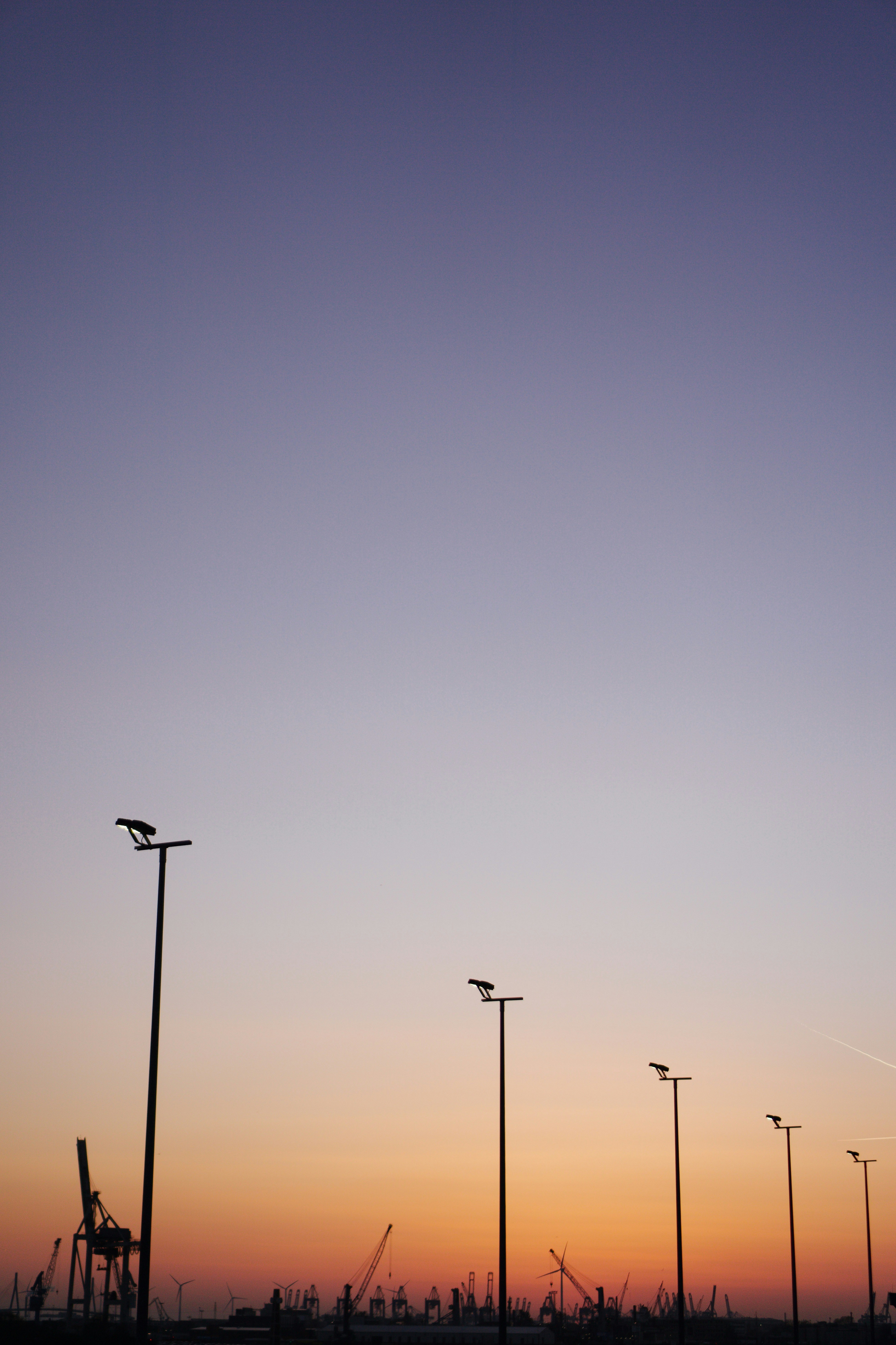 Edge of Dusk: Silhouetted Light Poles Across a Quiet Harbor