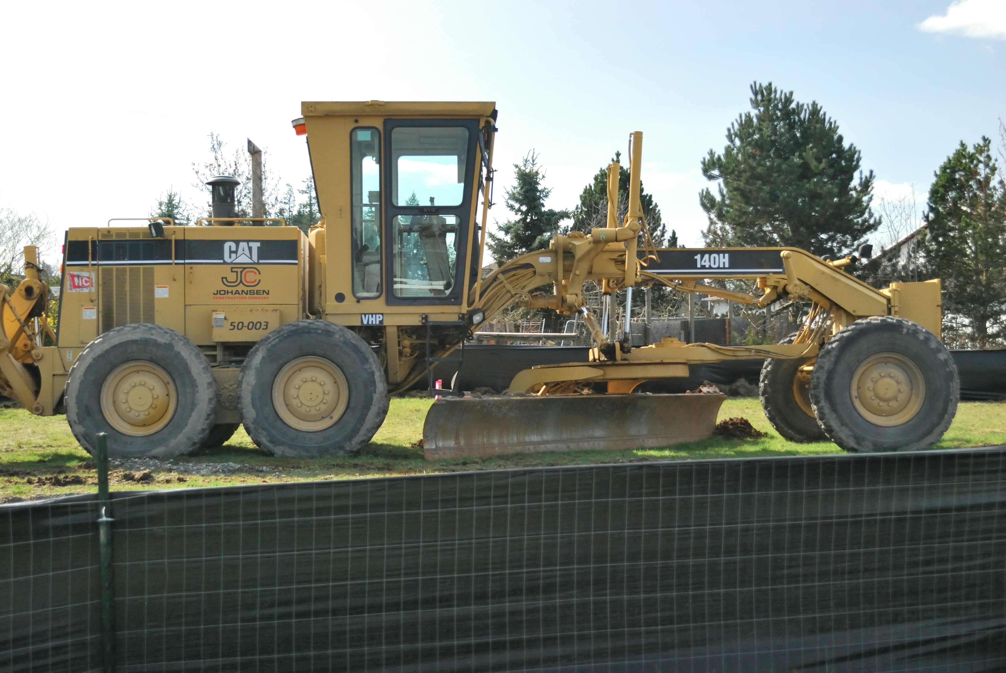 Yellow earthmover on a fenced construction site poised for work