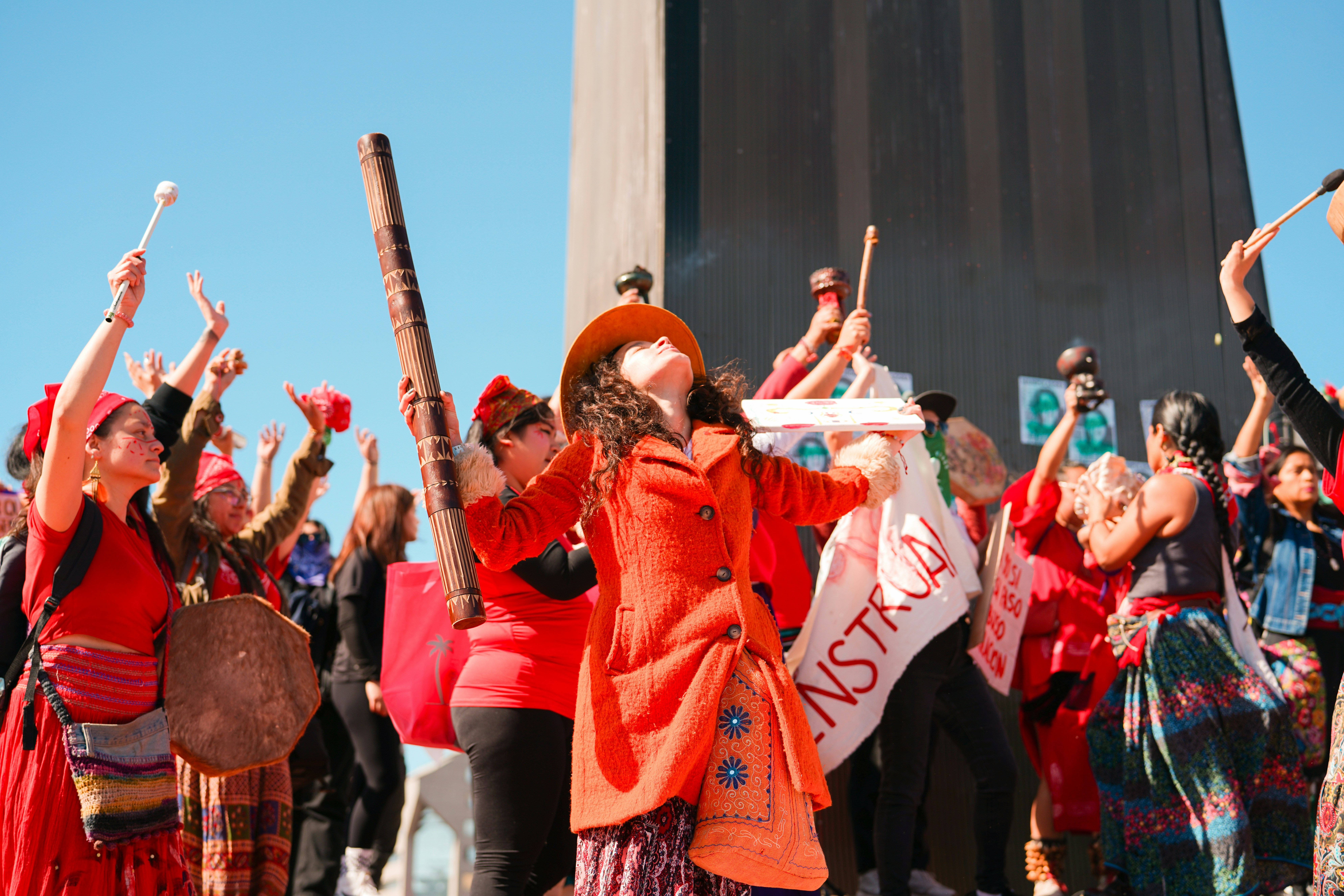 Fiery procession under a blue sky: a crowd in red and orange leading a rhythmic march