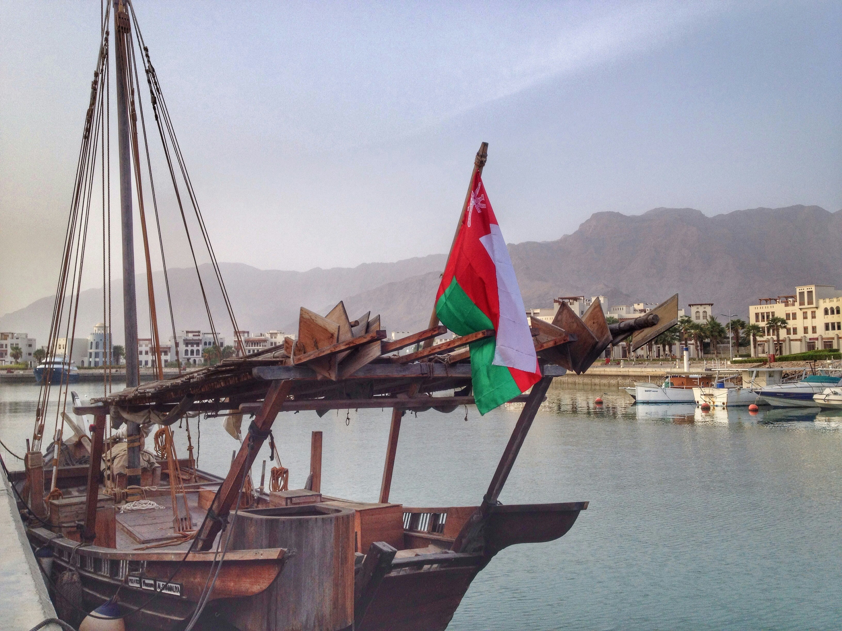 Red Flag on a Timber-Wrecked Vessel in a Quiet Seaport