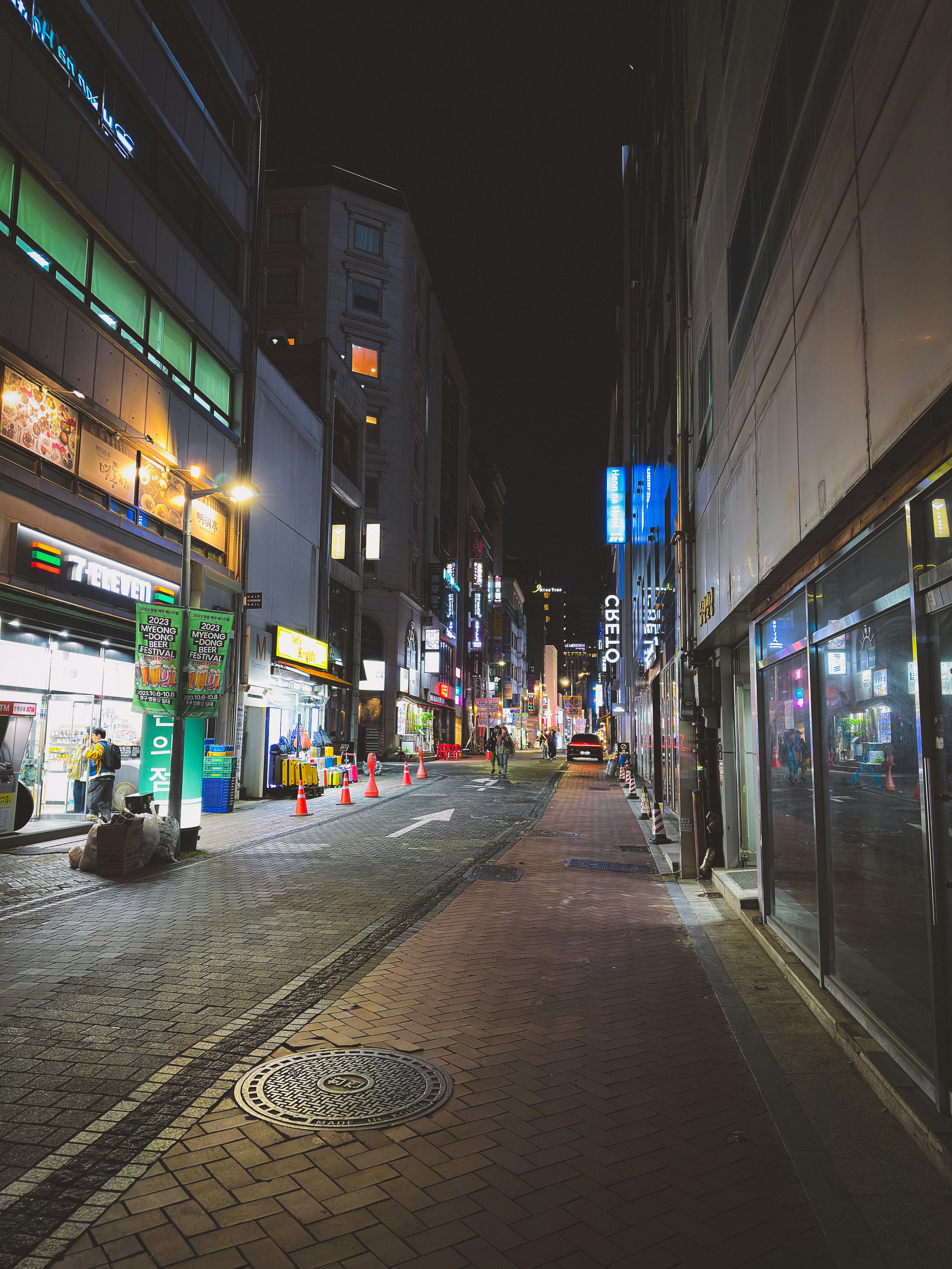 A city street at night with buildings and a person sleeping on the ...