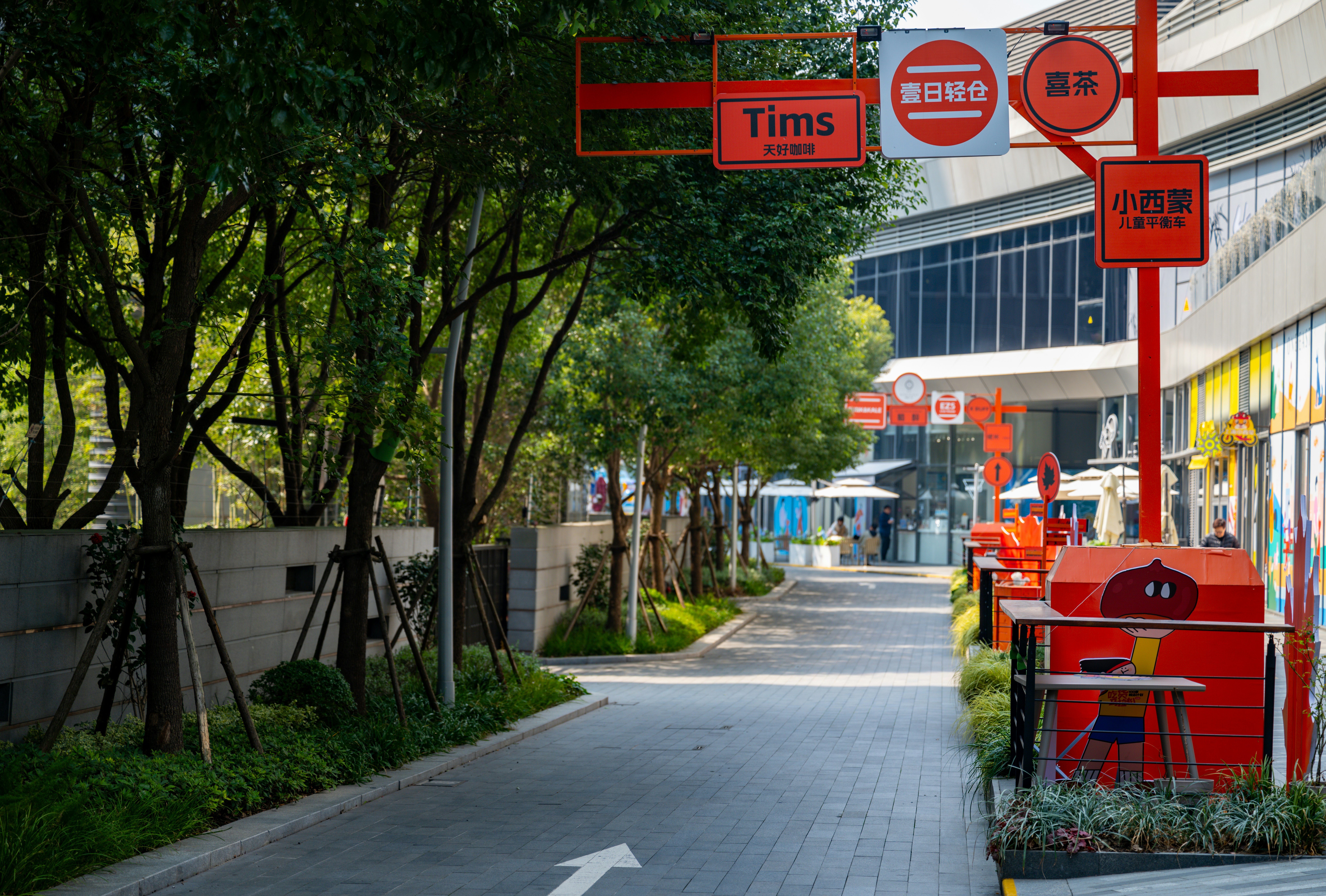 Red Signage and Green Canopy: A Quiet Urban Walkway
