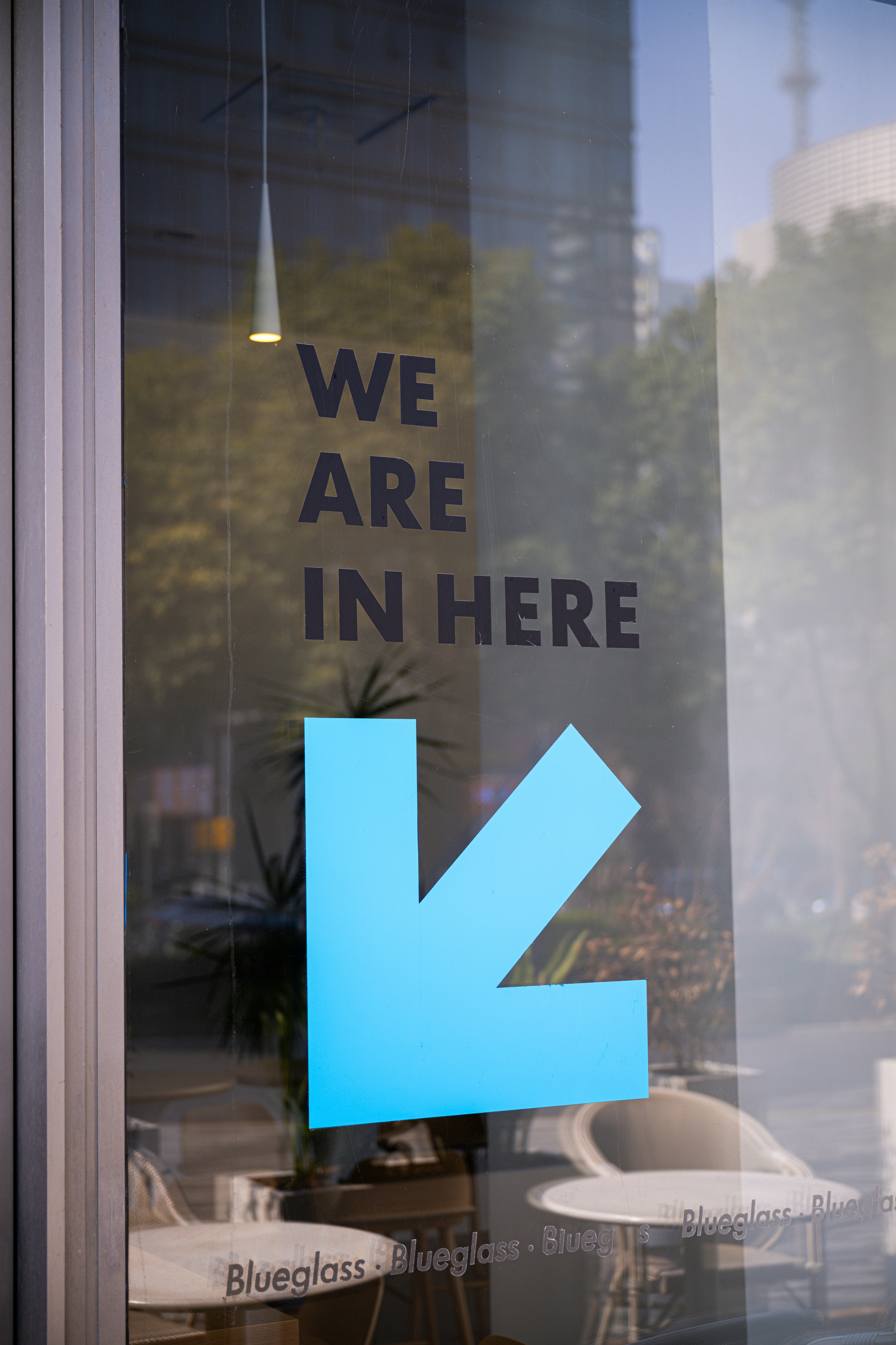 We Are In Here: Bold Blue L Anchors a Glass-Front Urban Window