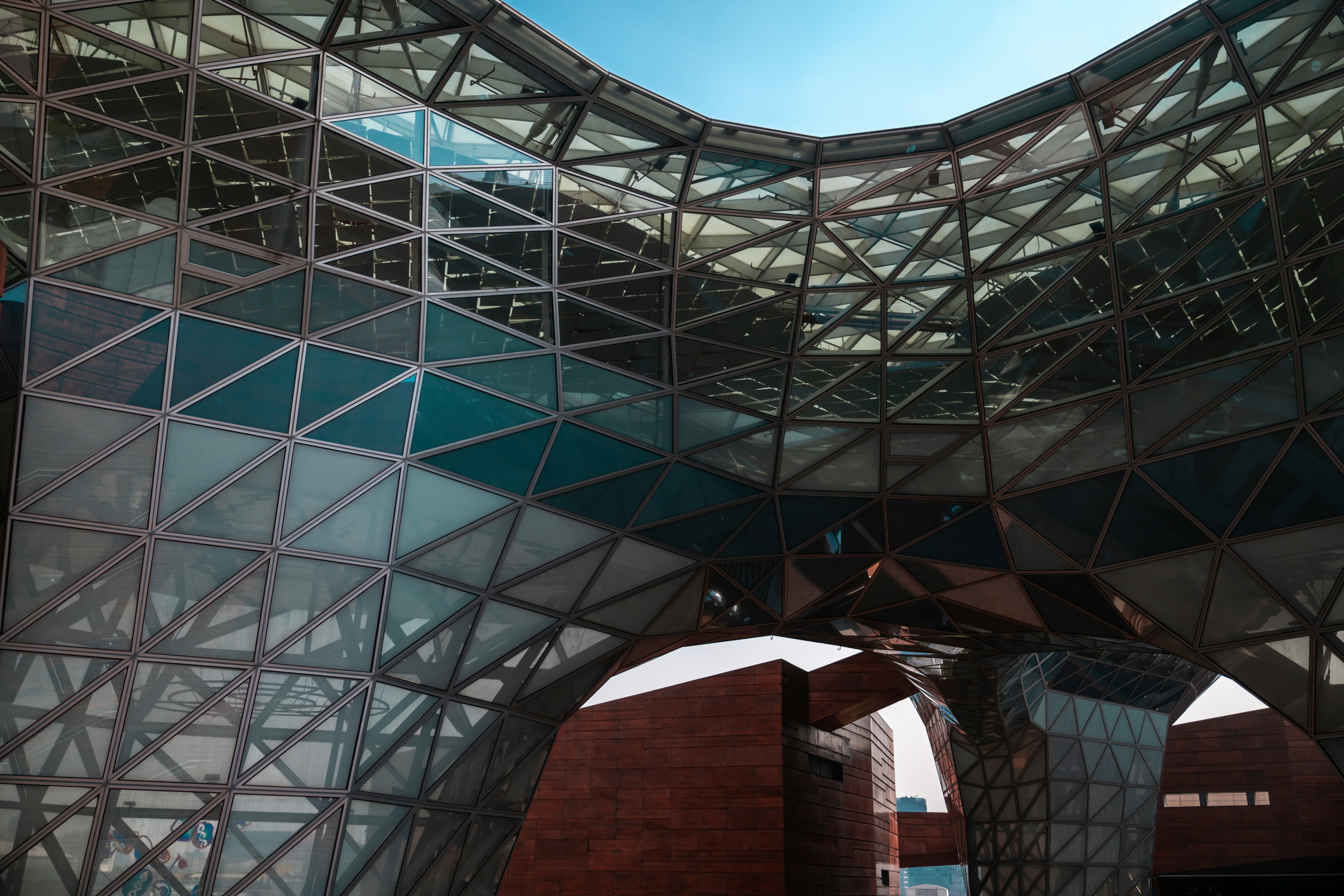 Geometric Glass Canopy Framing a Brick Arch Under a Blue Sky