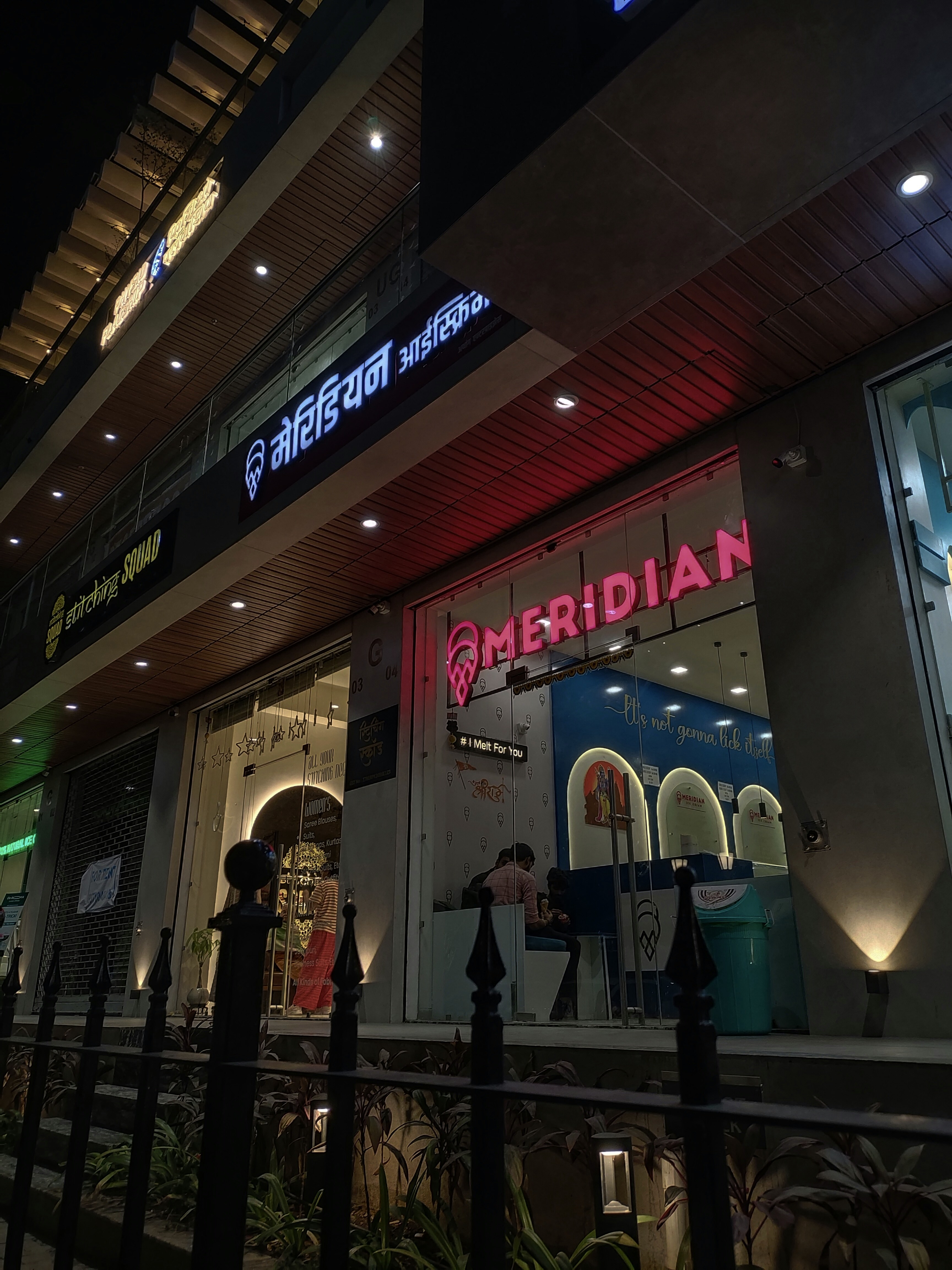Street view of a brightly lit ice cream shop with neon signs at night.